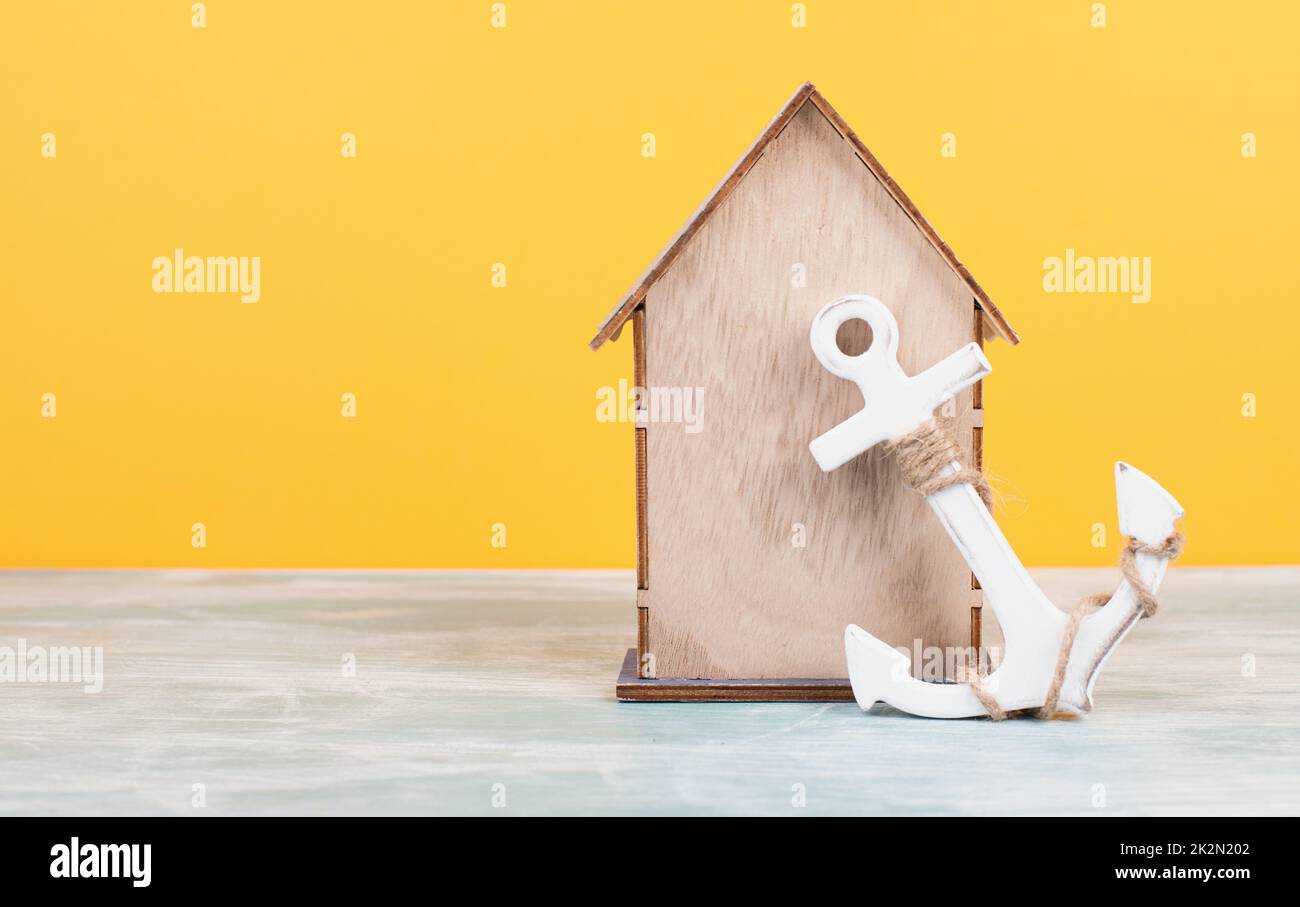 Wooden house with an anchor, yellow background, buying or renting a ...