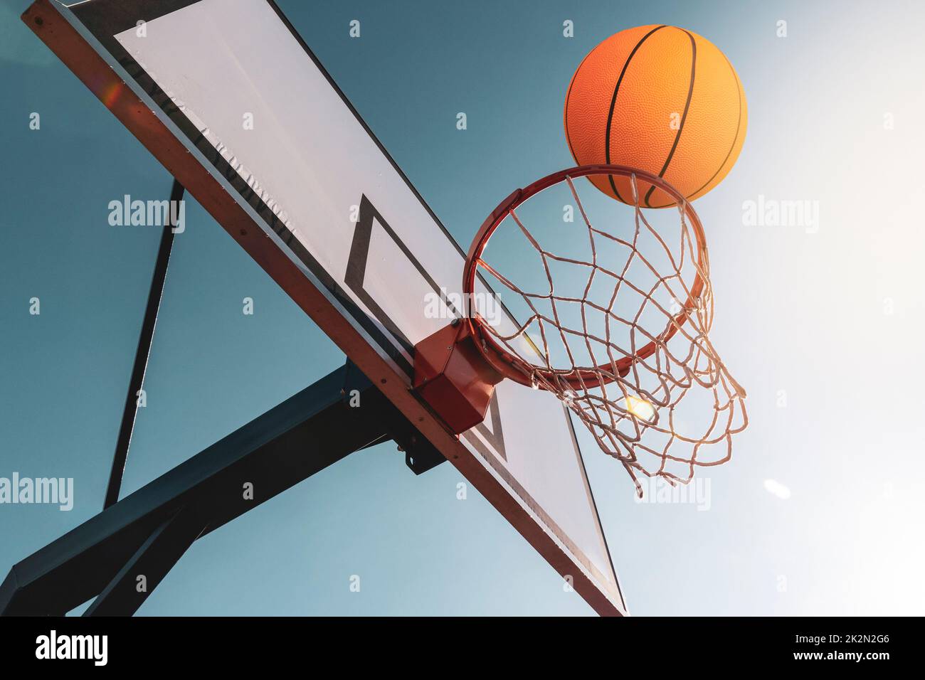 Orange ball above the hoop net with blue sky in the background Stock ...