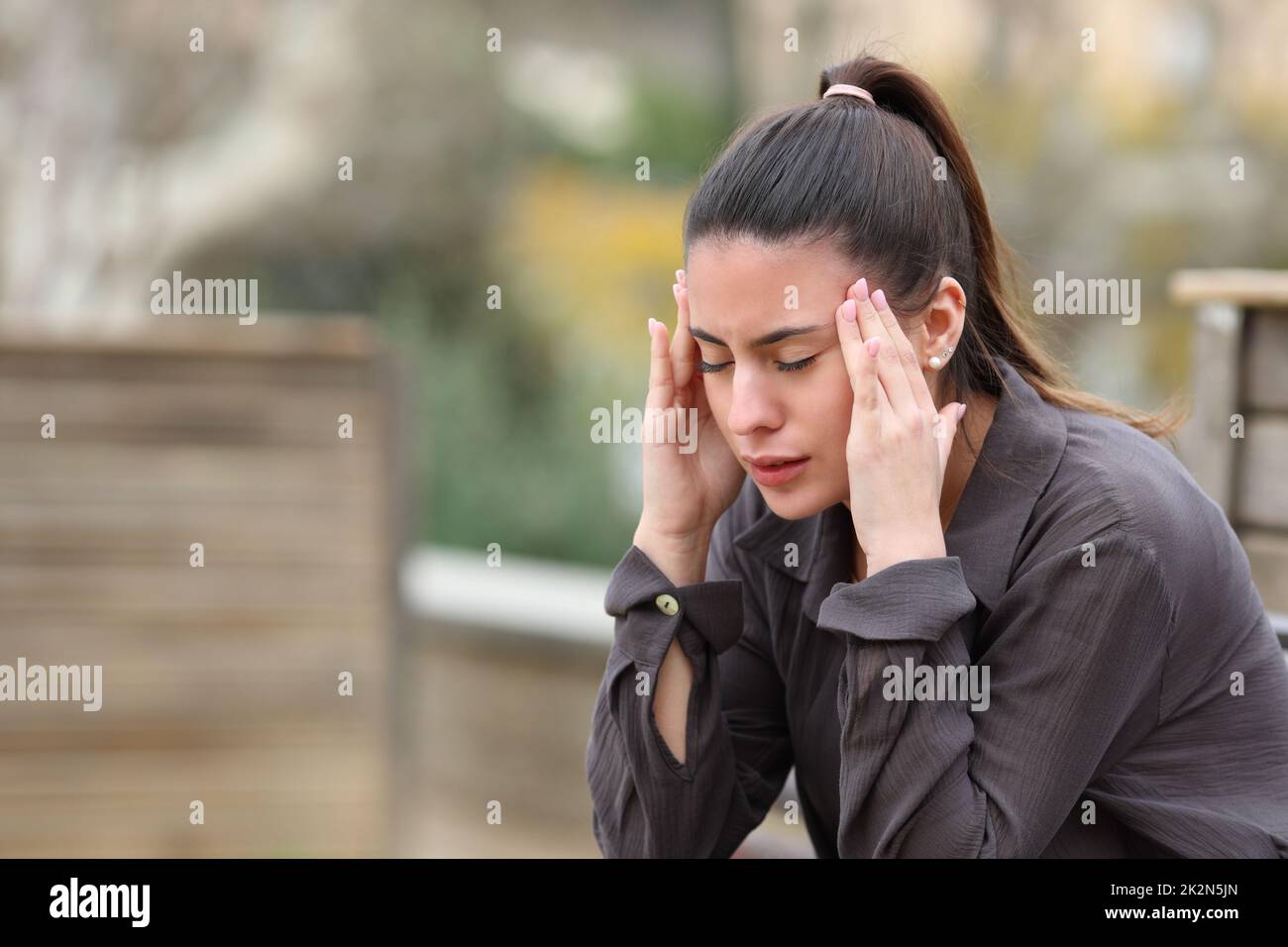 Teen suffering migraine complaining sitting on a bench Stock Photo - Alamy