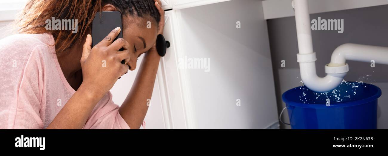 Woman Calling Plumber In Front Of Leaking Sink Pipe Stock Photo - Alamy