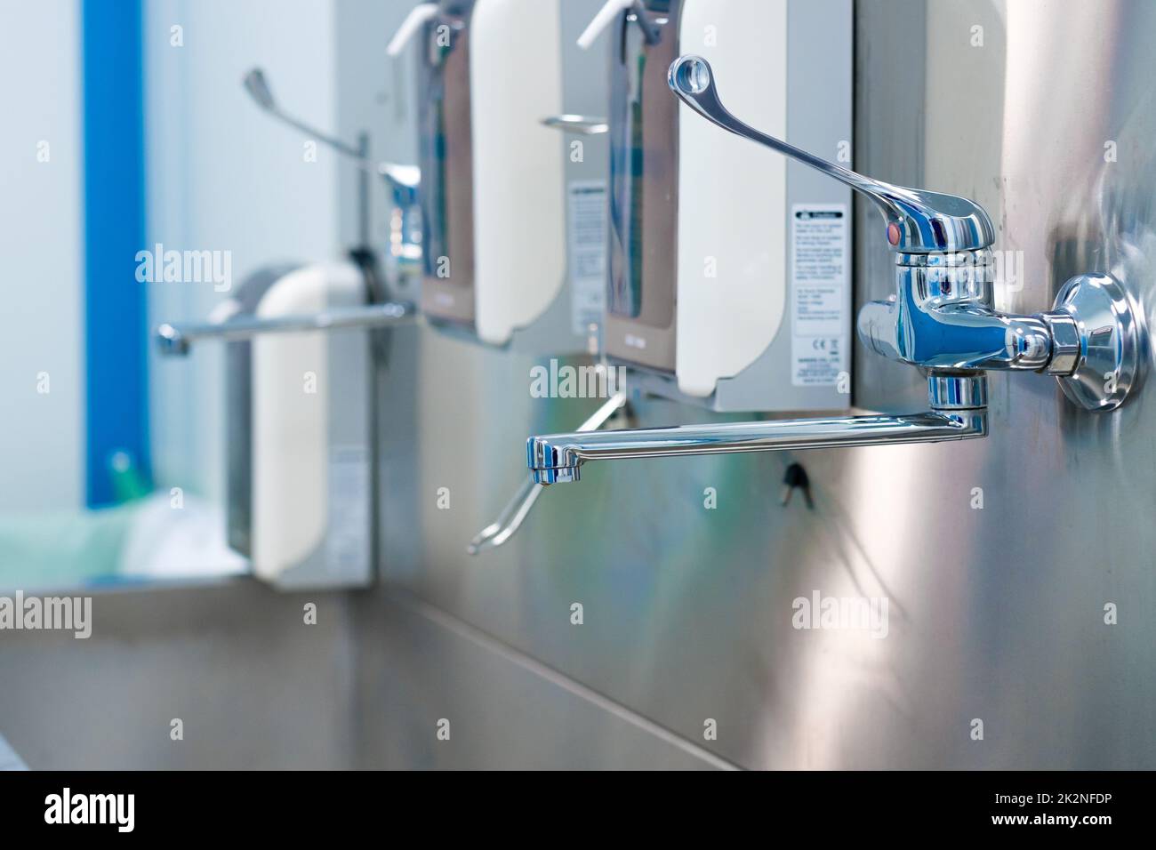 Selective focus on a shiny faucet of a sterile steel washbasin in a ...