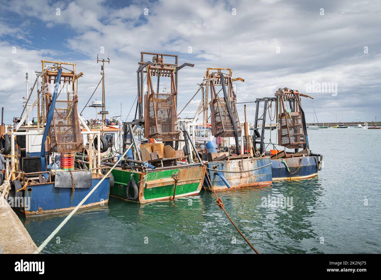 Four small fishing boats with shellfish cages moored in Howth harbour ...
