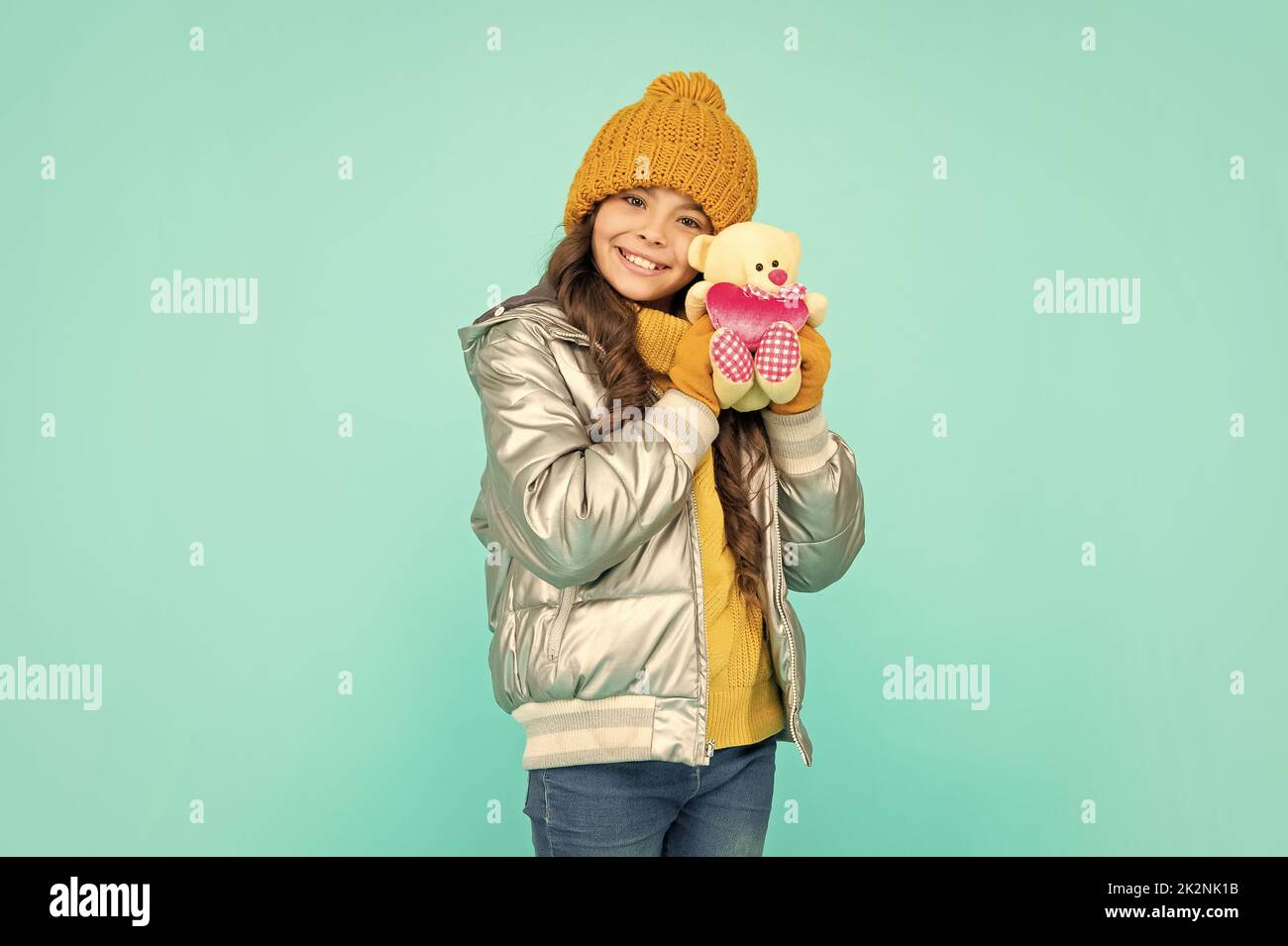 happy teen girl in winter clothes hold toy on blue background ...