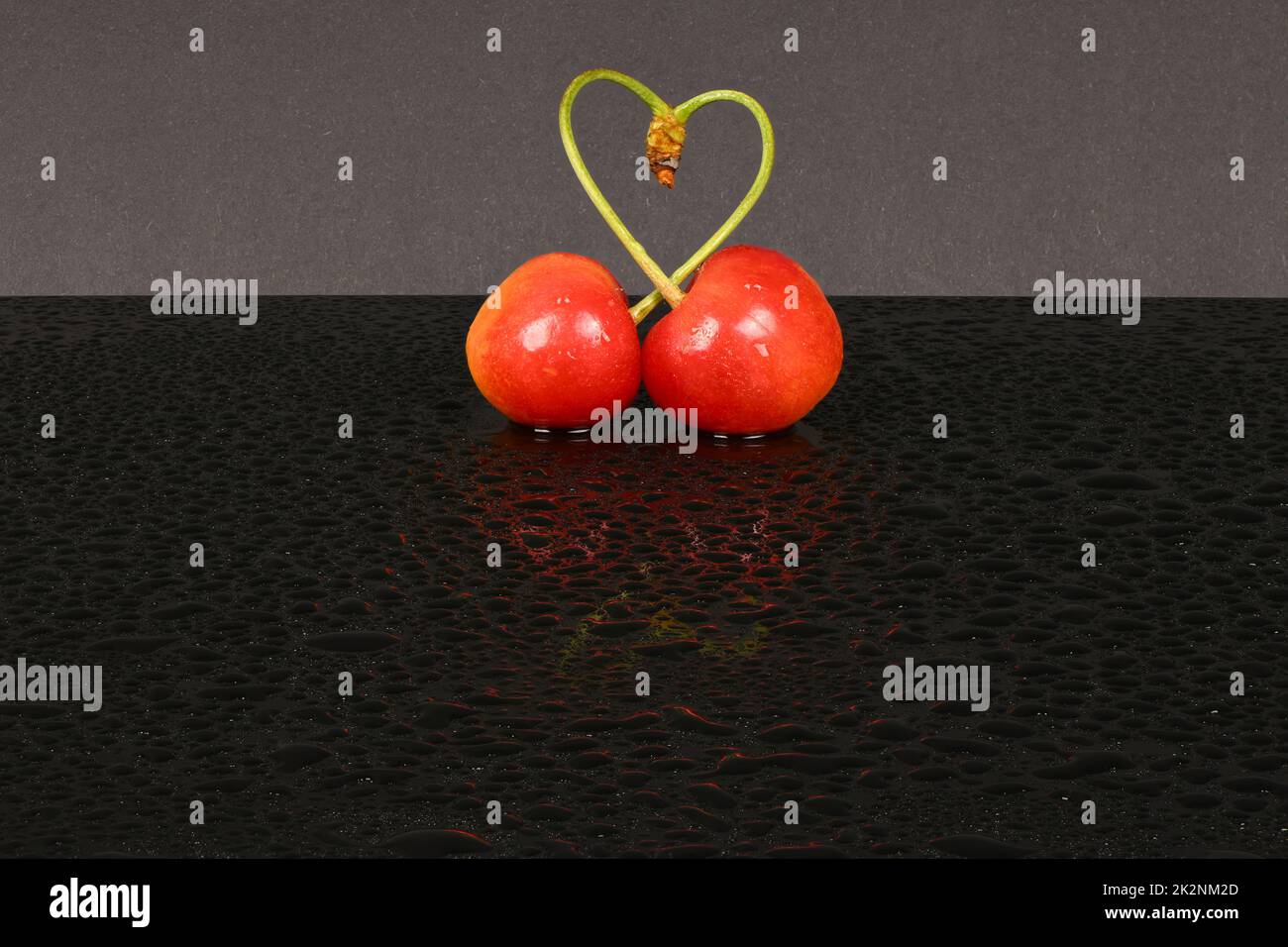 Two heart-shaped cherries on a black acrylic background. High ...