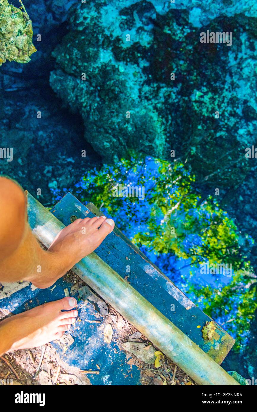 Feet at blue turquoise water limestone cave sinkhole cenote Mexico ...
