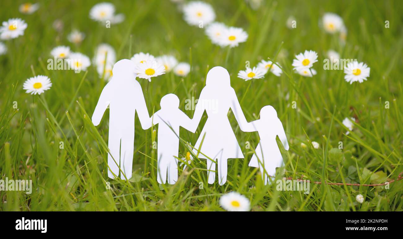 Family paper cut out is standing in a meadow, parents with daughter and ...