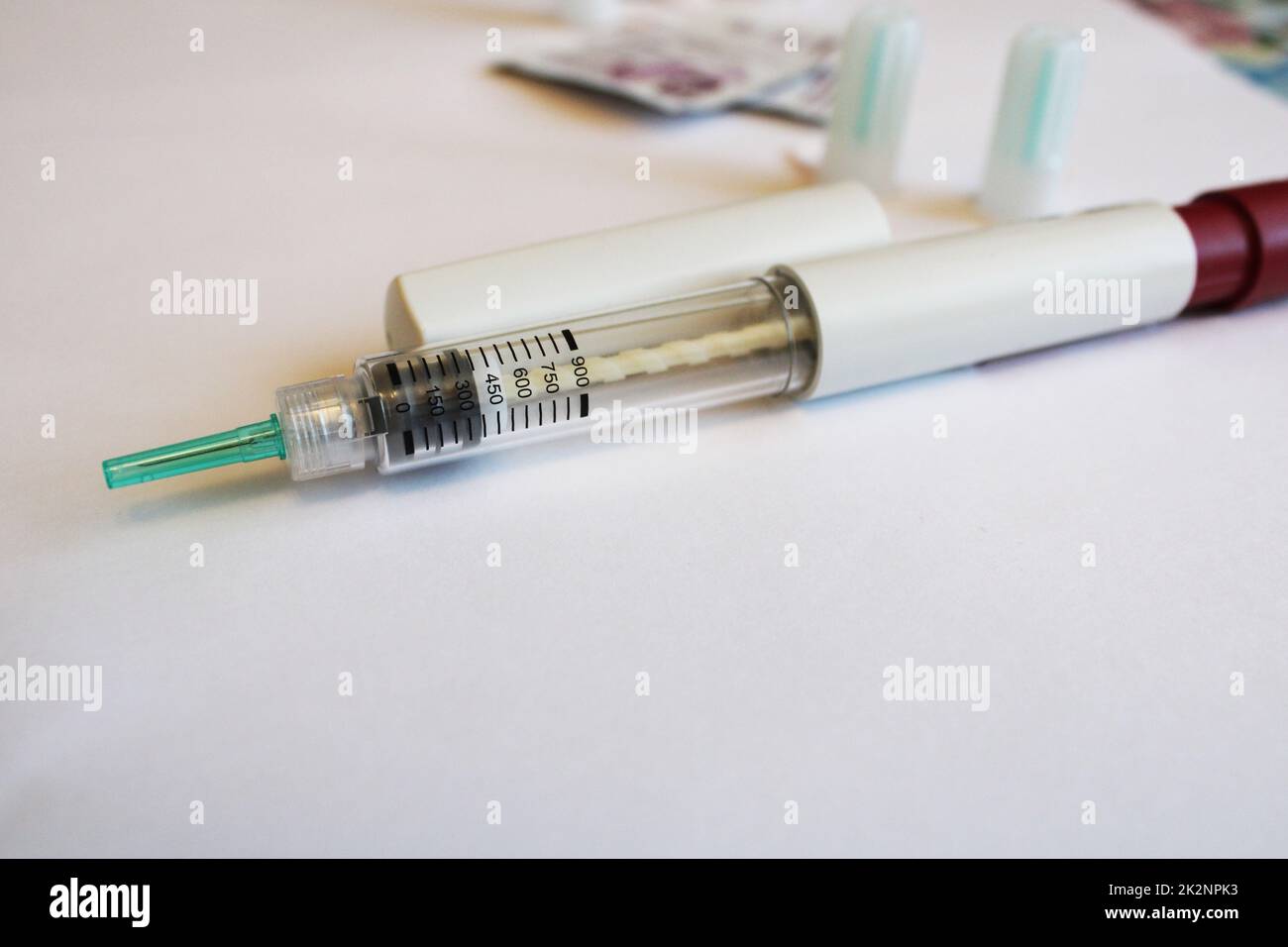 Injection syringe on a white table with spare needles in the background ...