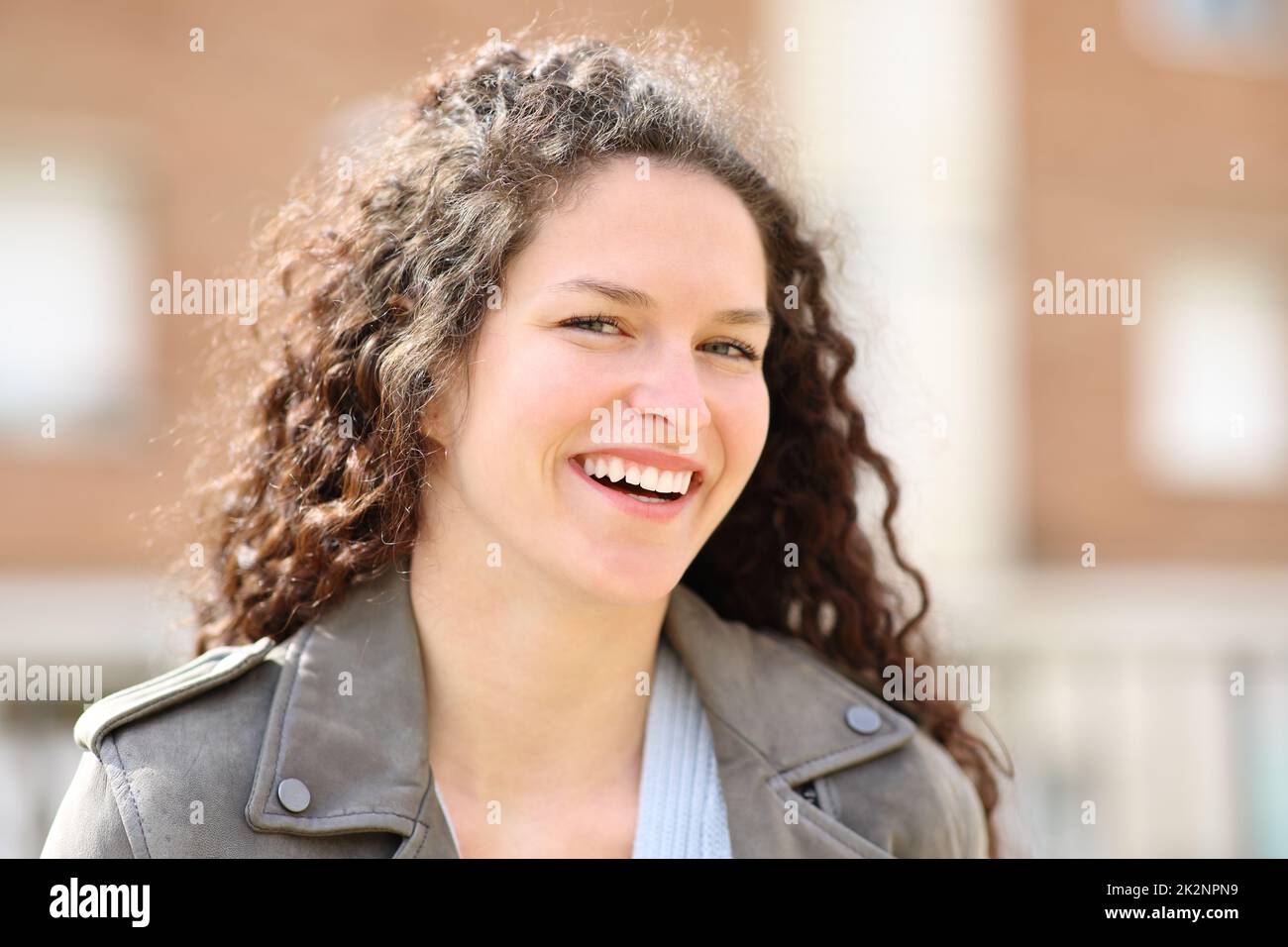 Happy woman smiling at camera standing in the street Stock Photo - Alamy