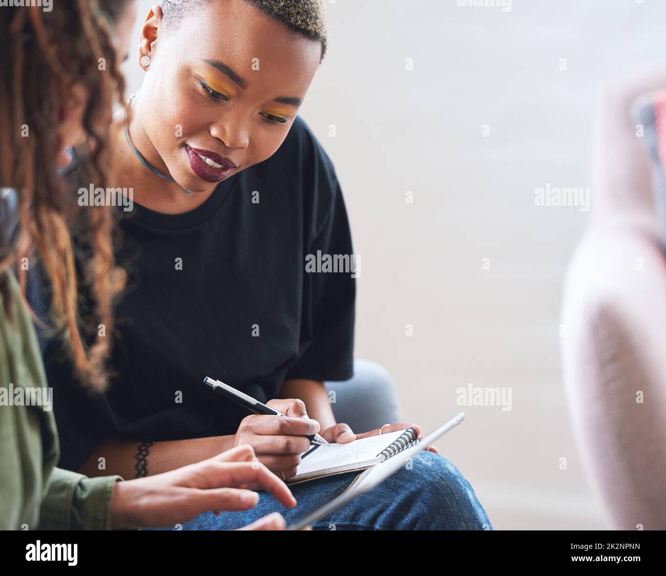 African american woman writing notes with friend showing ideas on ...