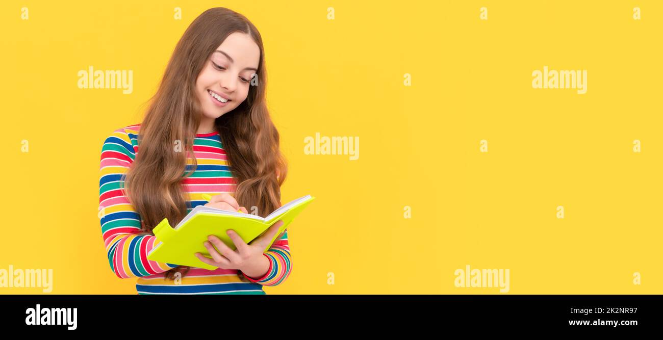 Happy girl child write down in copybook yellow background. Portrait of ...