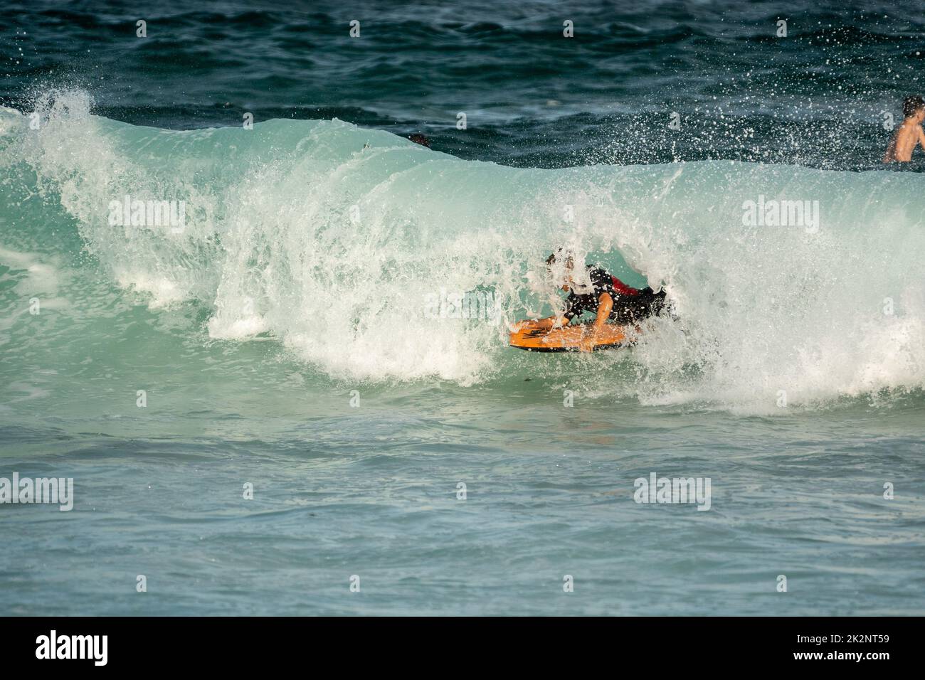 A surfer catching a wave, wearing a black wetsuit Stock Photo - Alamy