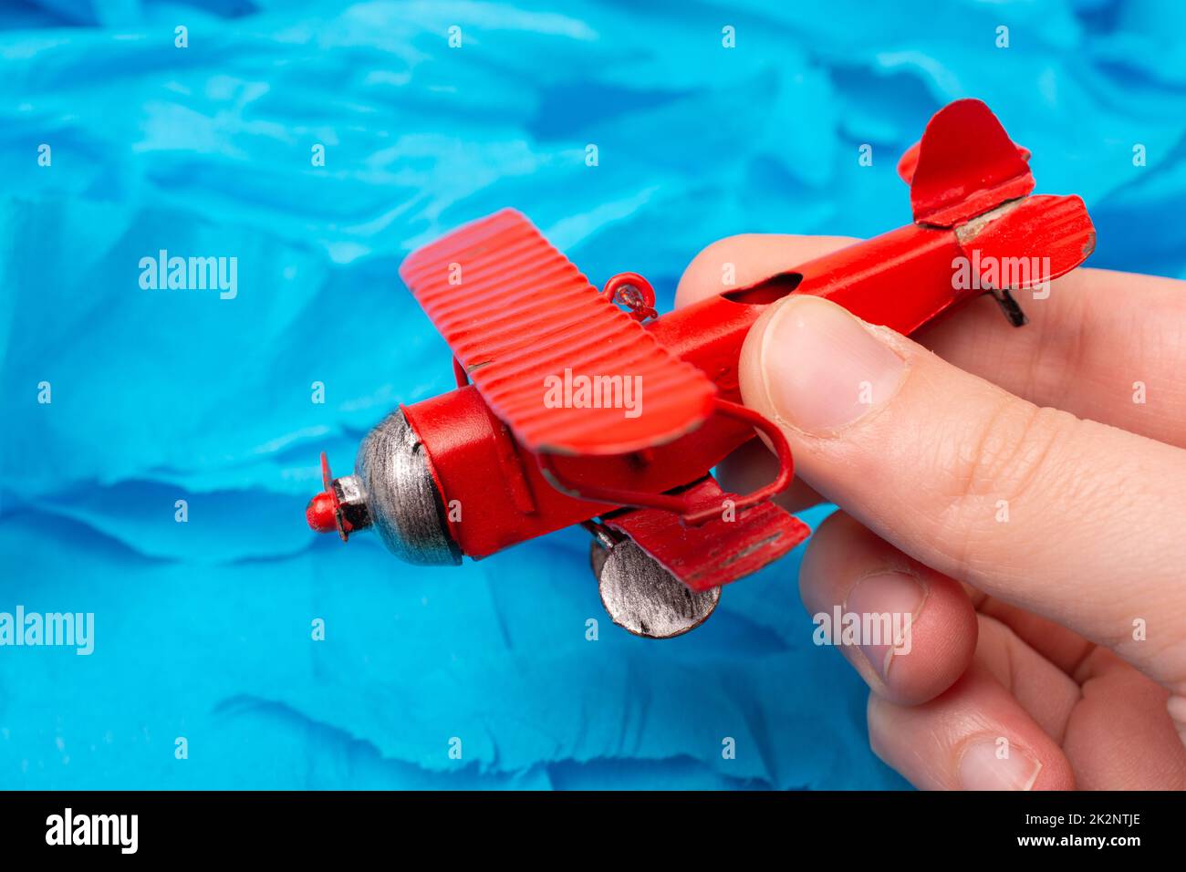 Hand holding a red toy plane on a blue background Stock Photo - Alamy