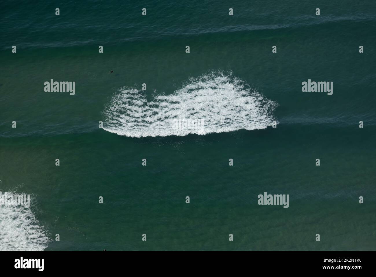 An aerial of sea tidal waves coming towards the shore on a sunny day ...