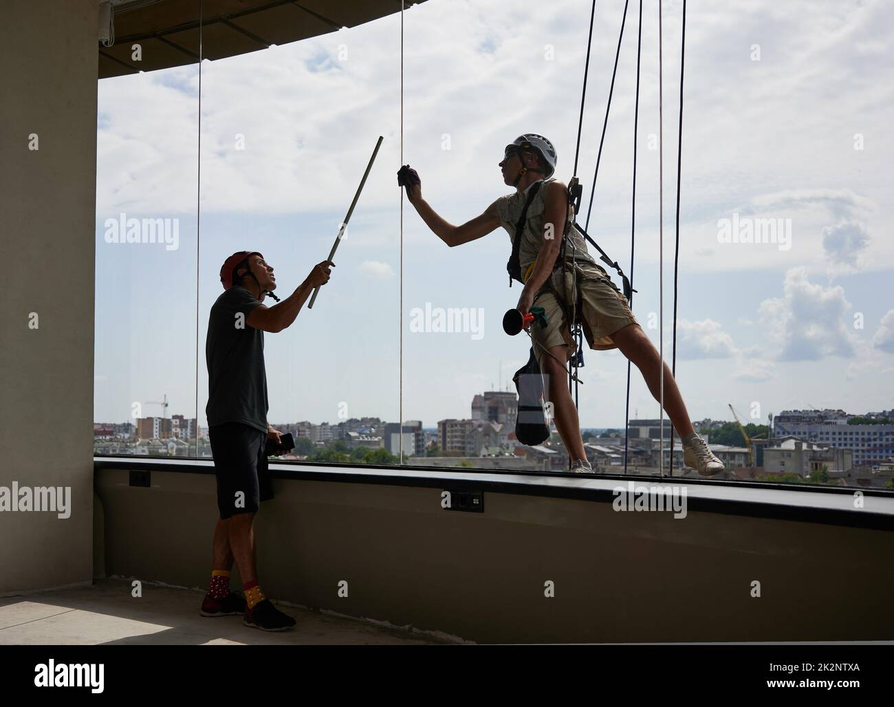 Industrial mountaineering professional cleaner hanging on rope and ...