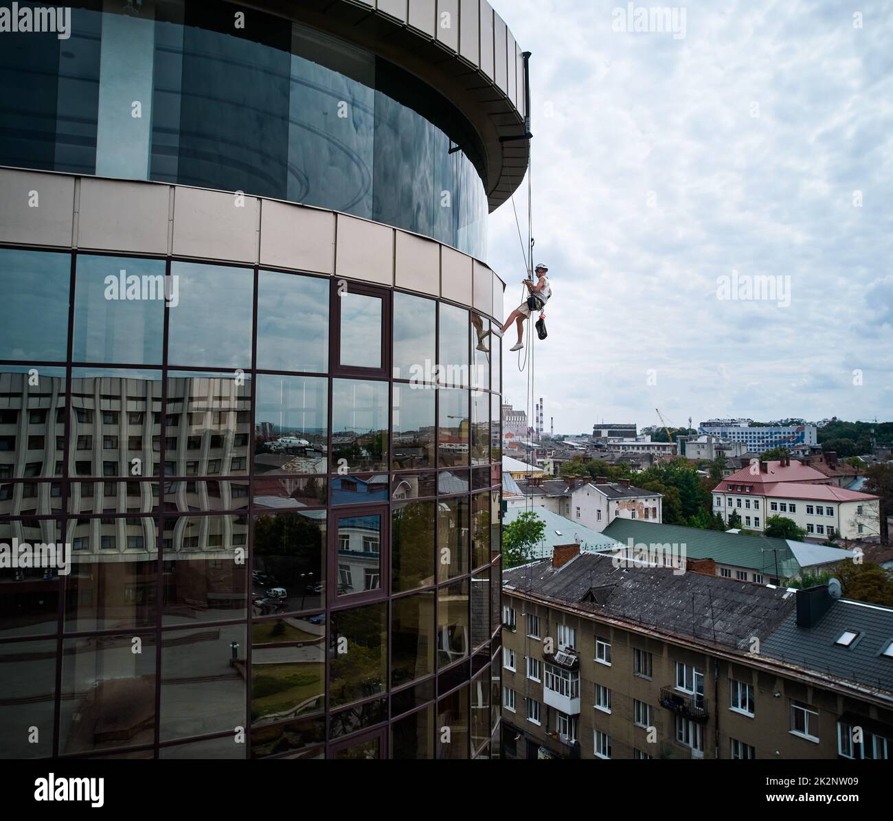 Industrial mountaineering professional cleaner hanging on climbing rope ...
