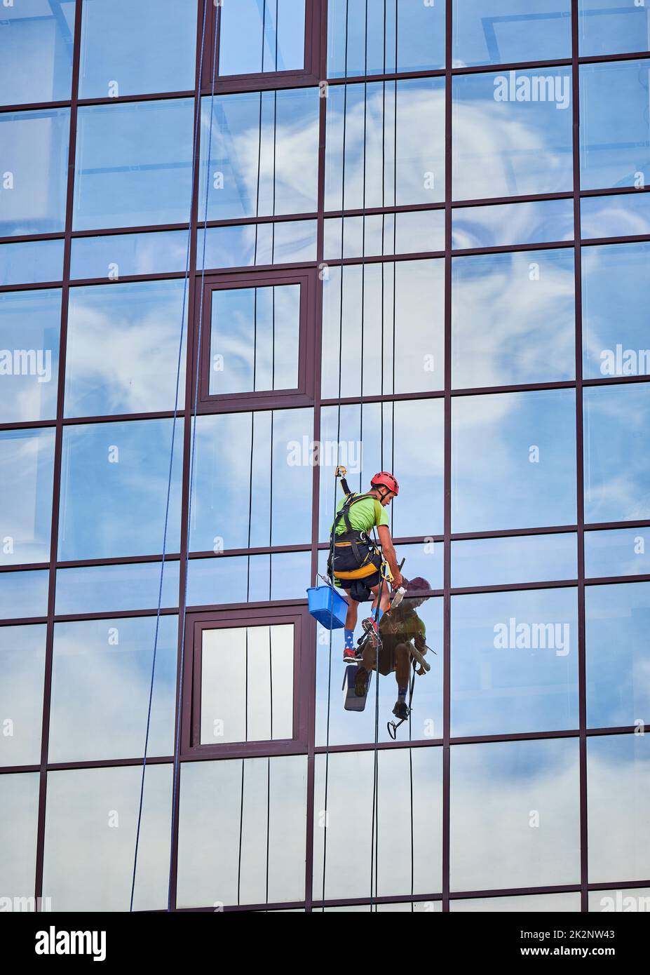 Industrial mountaineering worker washing glass windows of high-rise ...