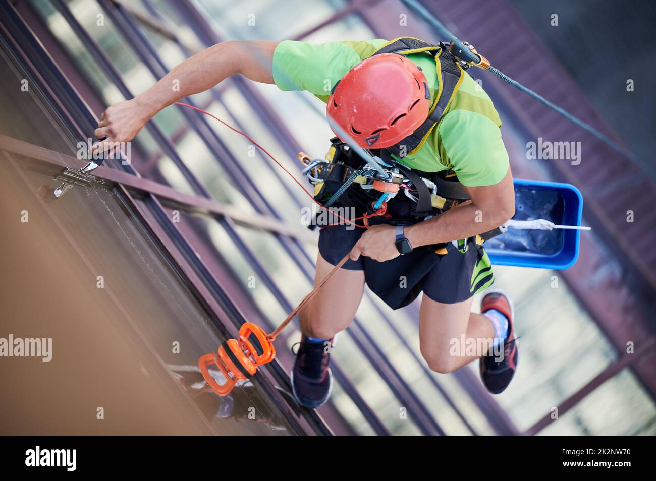 Industrial mountaineering worker washing glass windows of high-rise ...