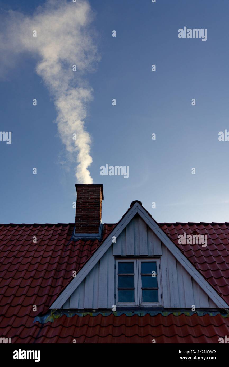 Woodsmoke coming out of the chimney of an old farmhouse climbs into a ...