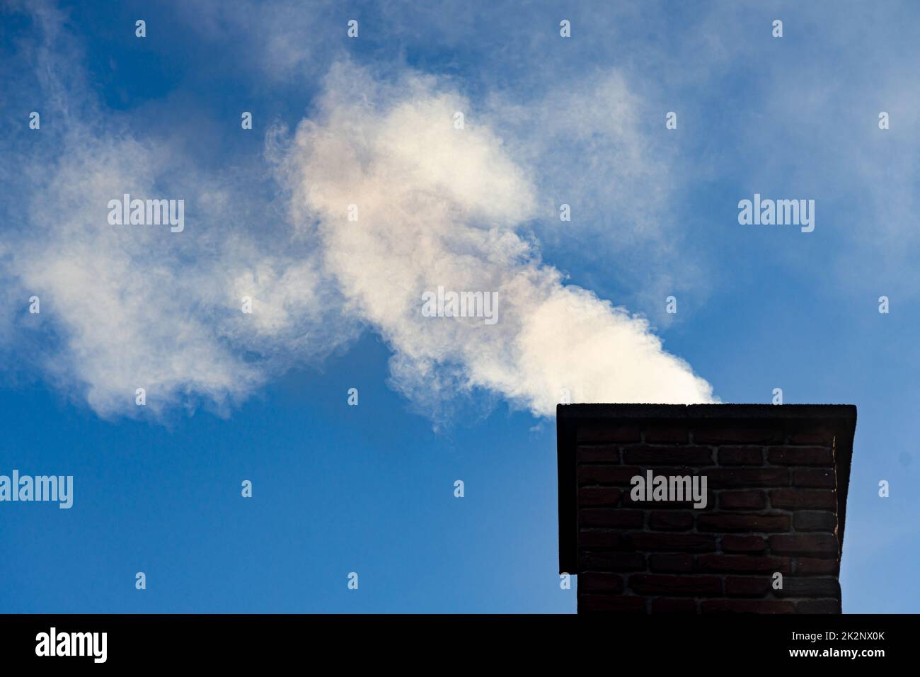 Woodsmoke coming out of the chimney of an old farmhouse climbs into a ...