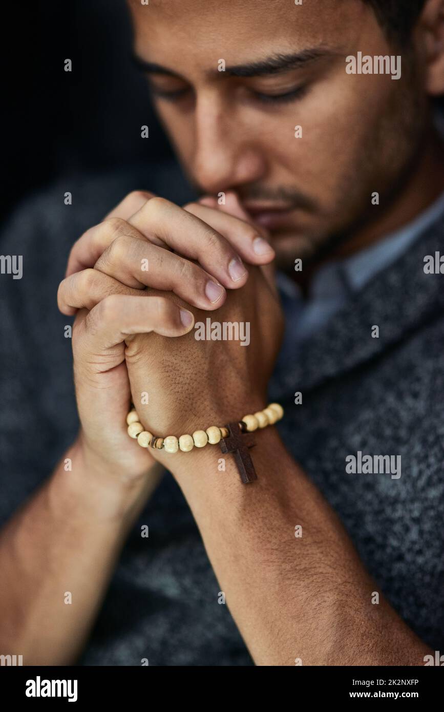 Praying for a miracle. Closeup shot of a young man praying with his ...