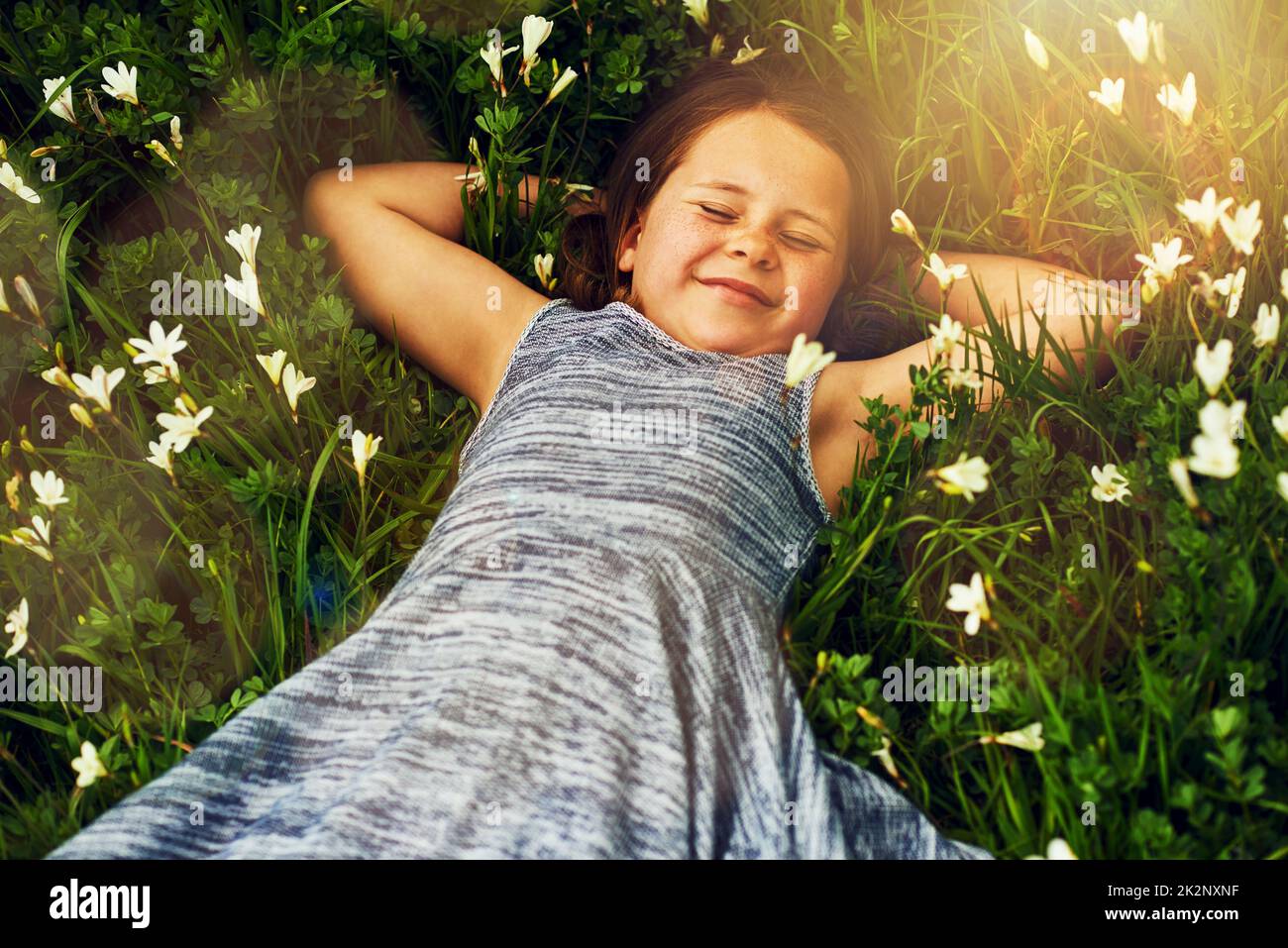 Making friends with the flowers. Shot of a cute little girl lying in a ...