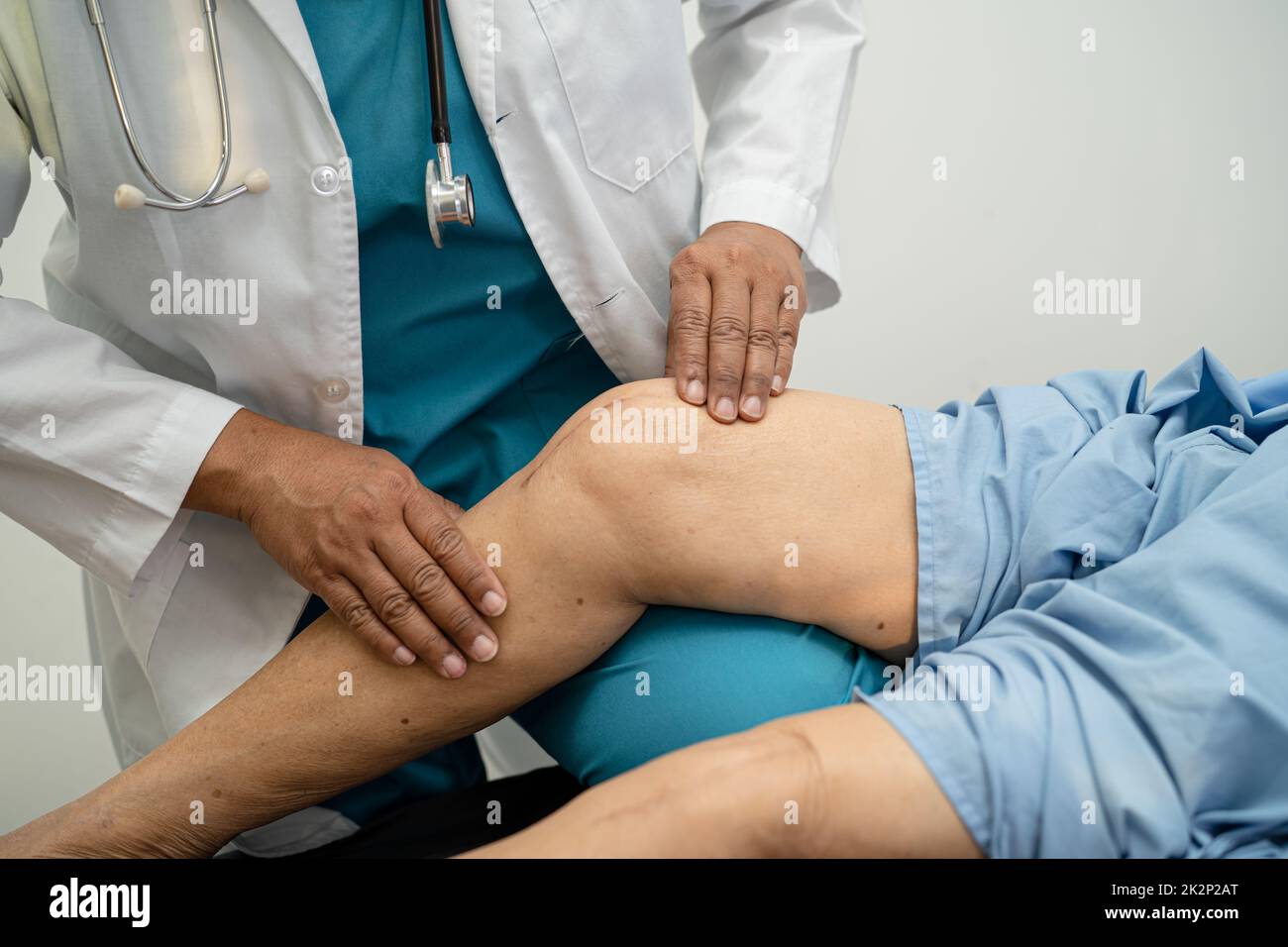 Asian doctor physiotherapist examining, massaging and treatment knee ...