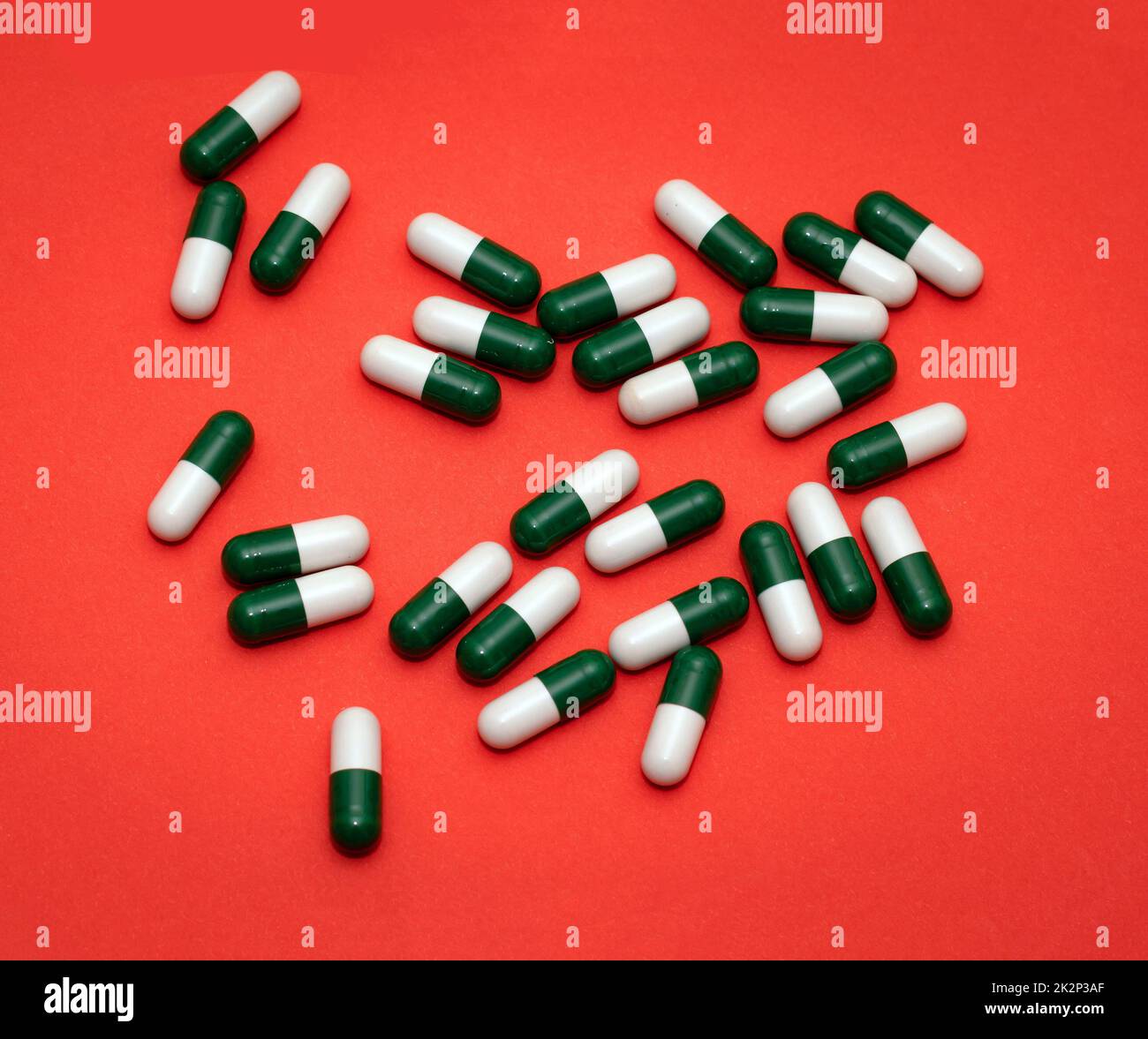 Pile of green and white capsules drugs on red background Stock Photo ...
