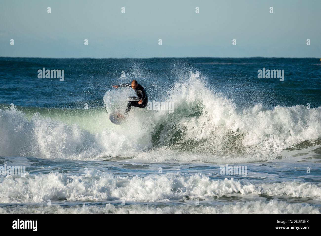 A young surfer catching waves before work on a early Friday morning at ...