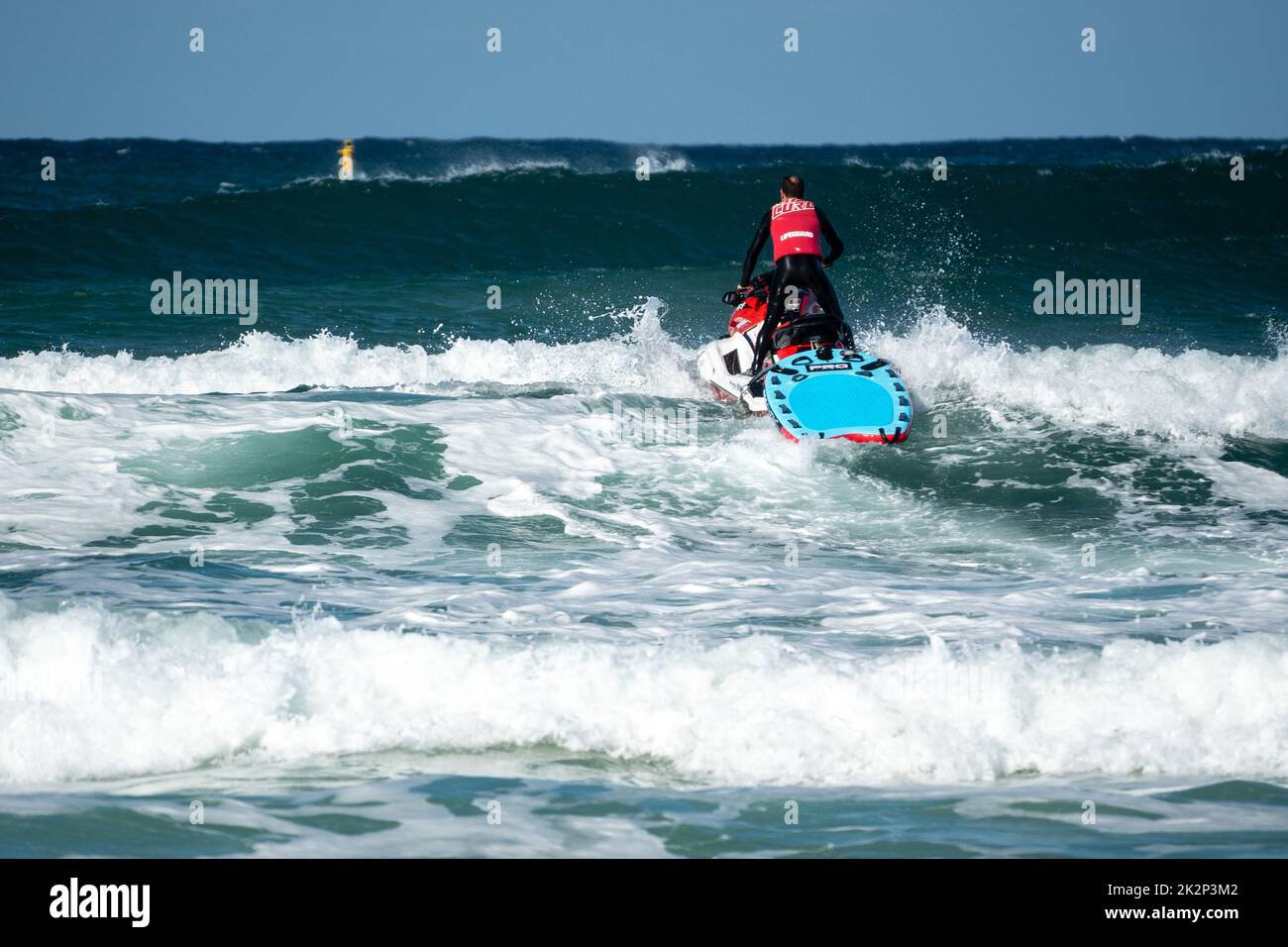A surf rescue team heading out into the ocean to rescue a person in ...