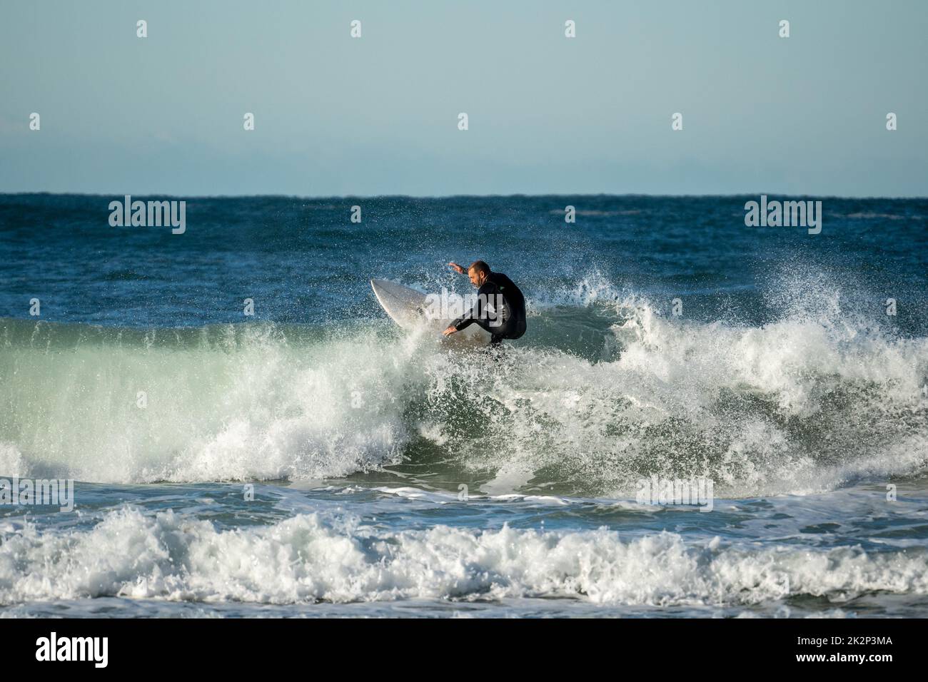 A young surfer catching waves before work on an early Friday morning at ...