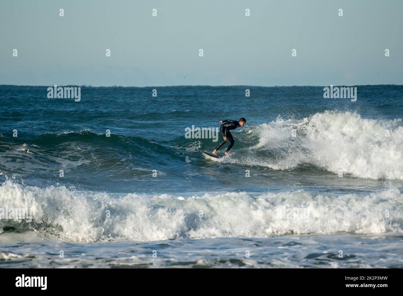 A young surfer catching waves before work on an early Friday morning at ...