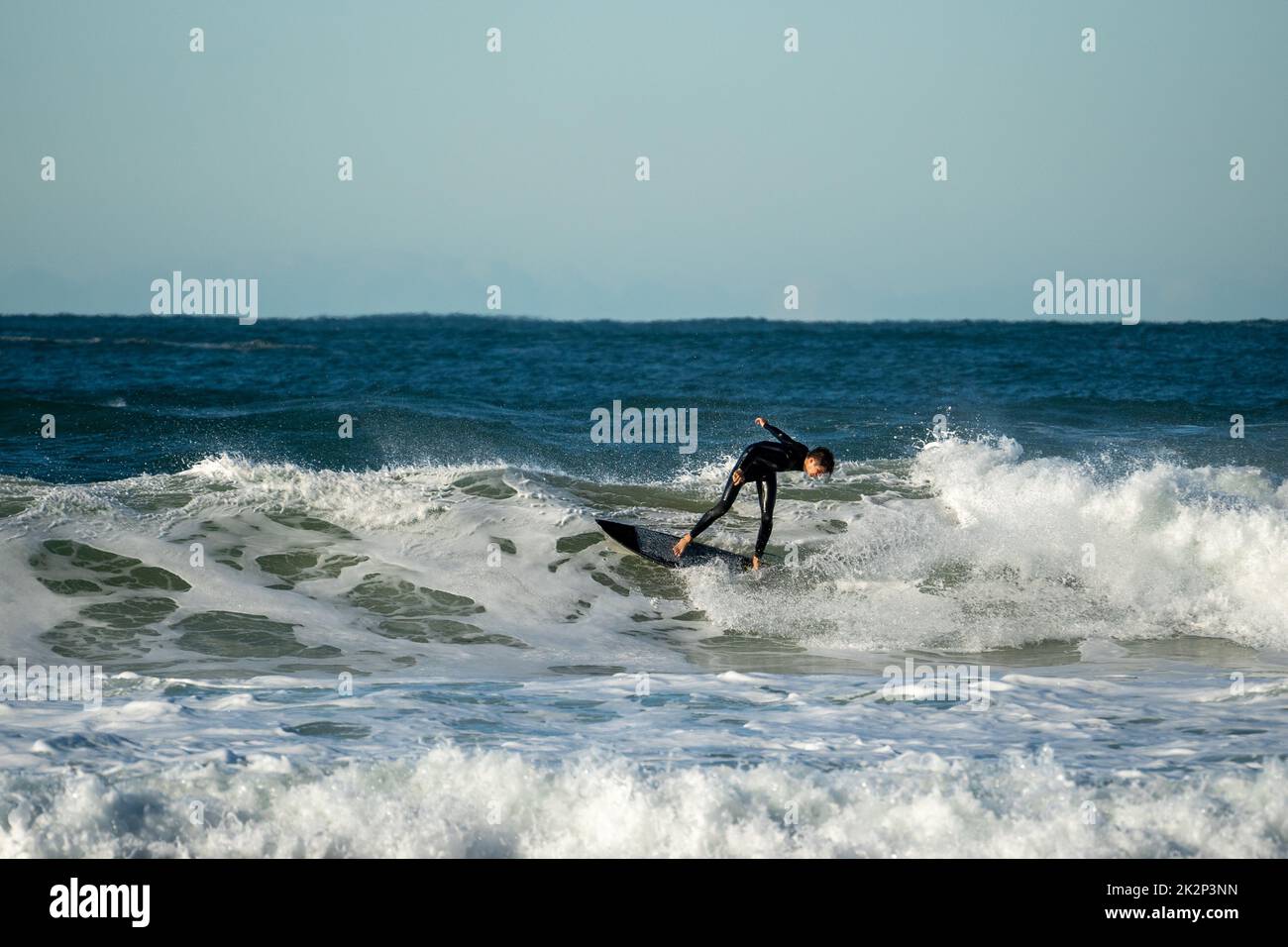 A young surfer catching waves before work on an early Friday morning at ...