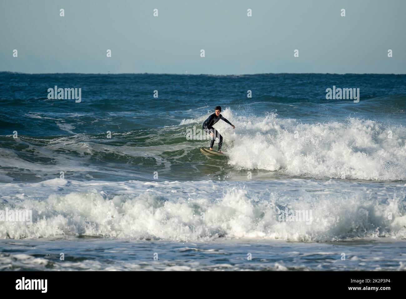 A young surfer catching waves before work on an early Friday morning at ...