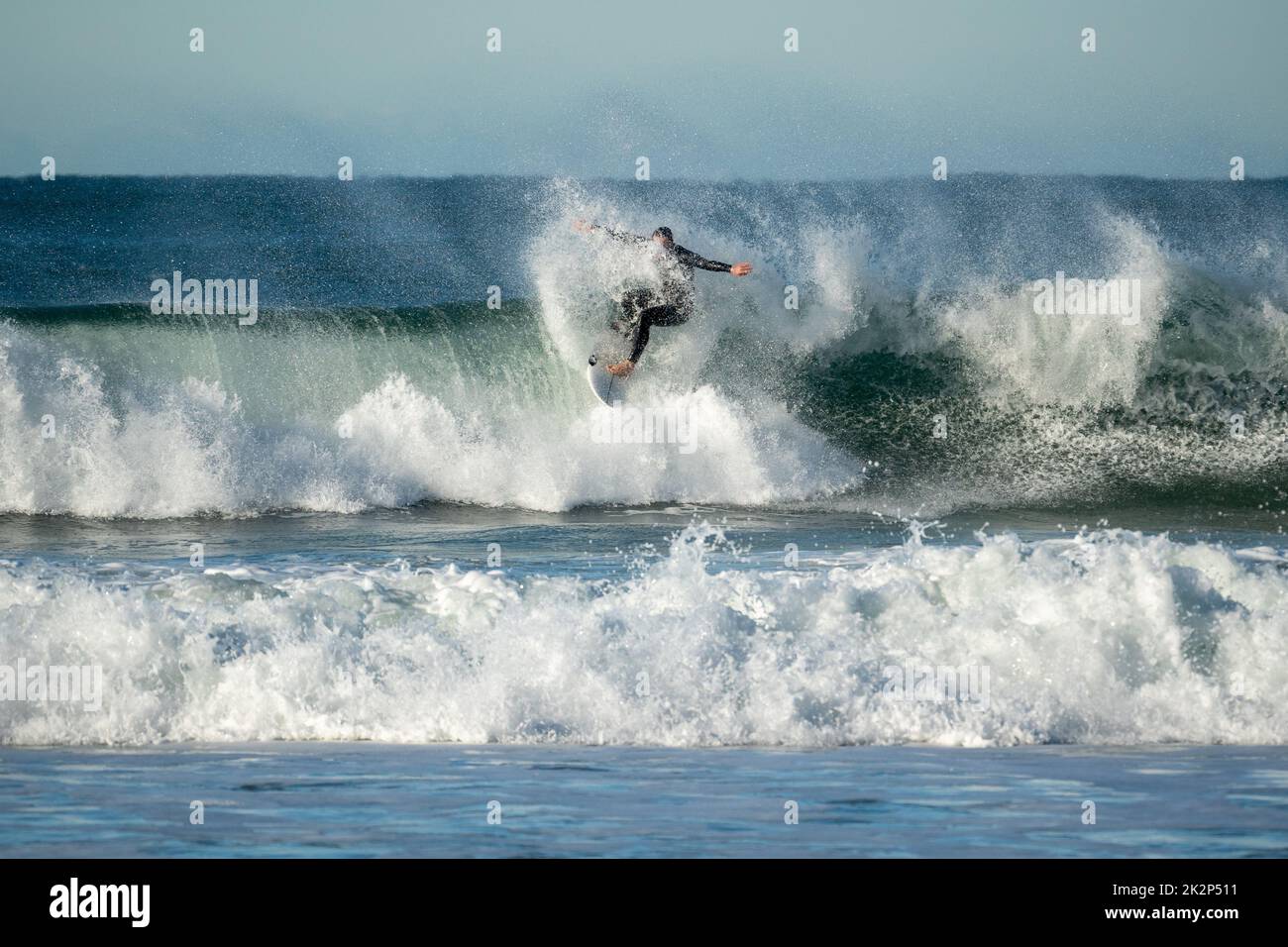 A young surfer catching waves before work on an early Friday morning at ...
