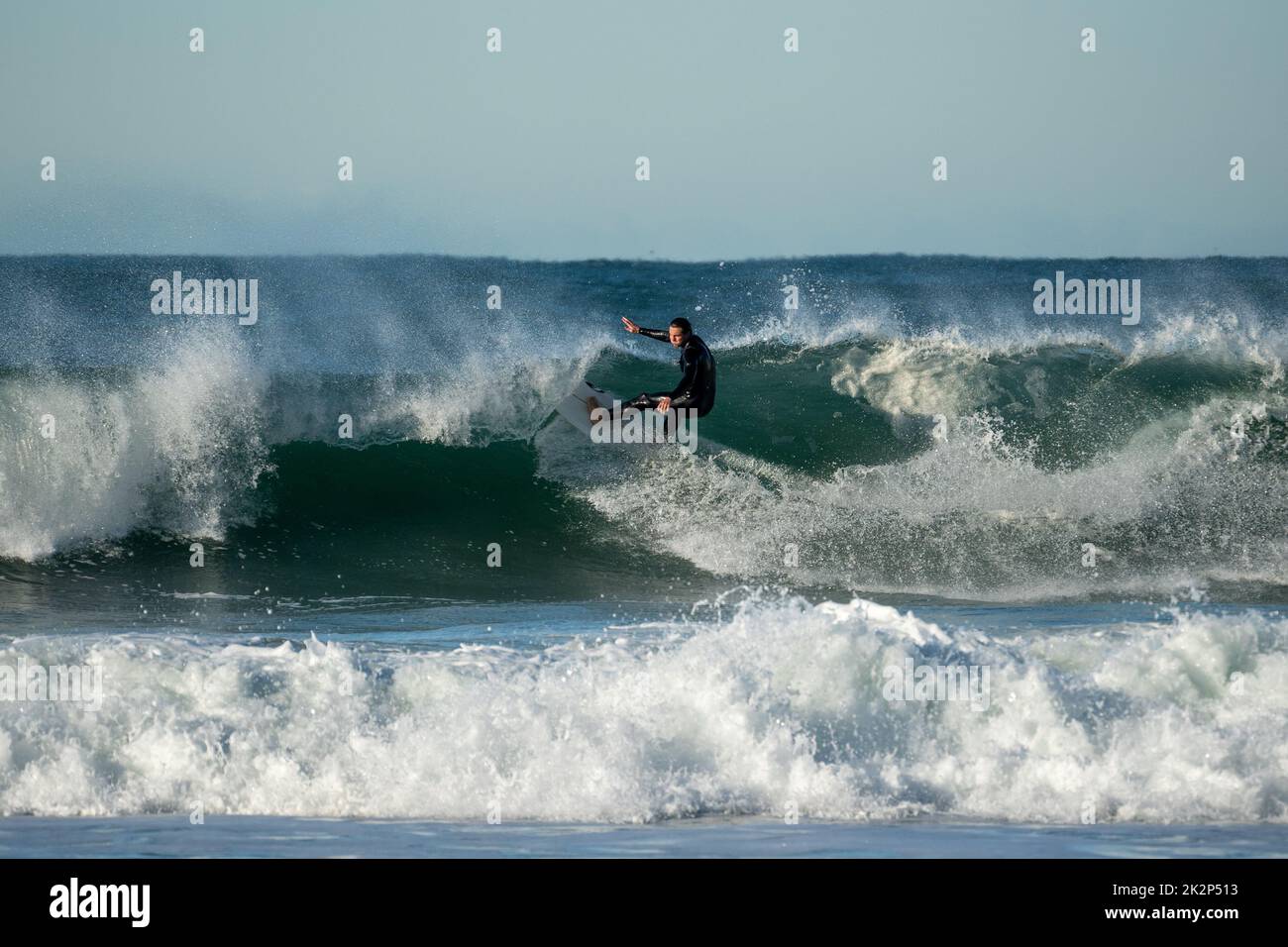 A young surfer catching waves before work on an early Friday morning at ...
