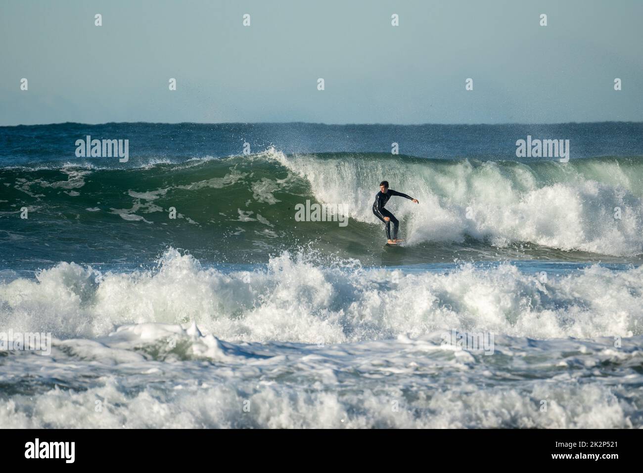 A young surfer catching waves before work on an early Friday morning at ...
