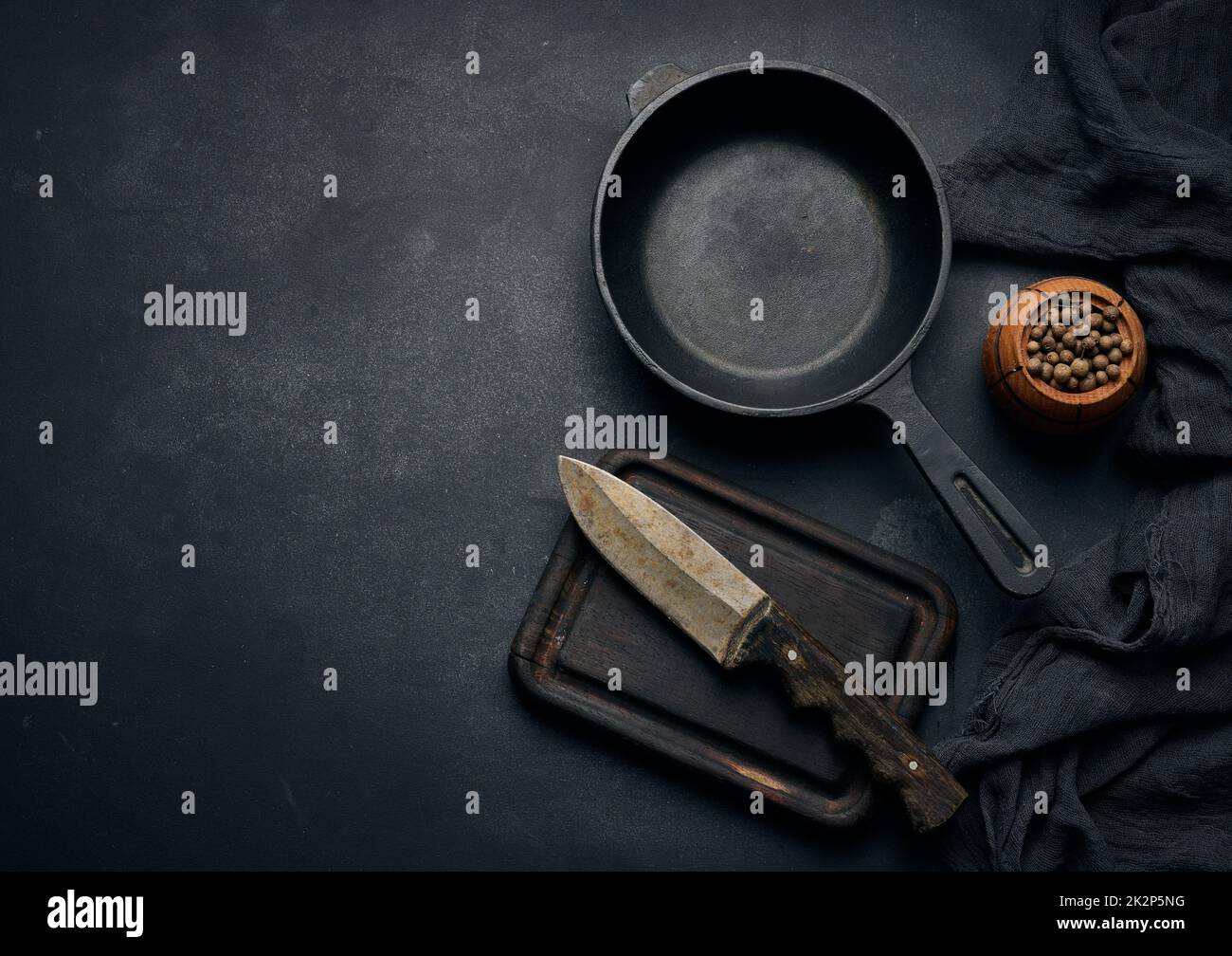 Empty round cast iron frying pan with wooden handle on black table, top ...