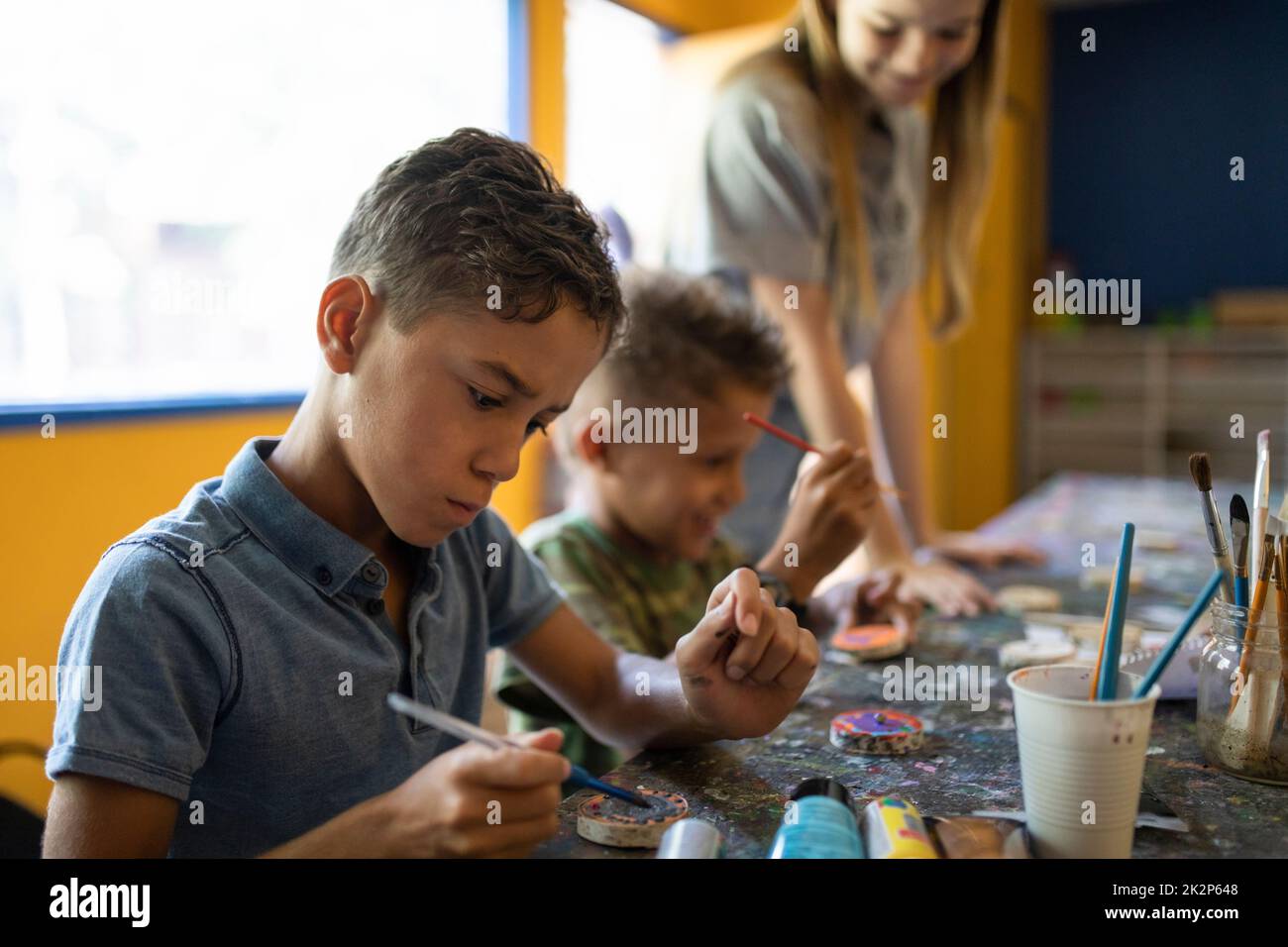 Boy decorating piece of wood in craft activity at summer camp Stock ...