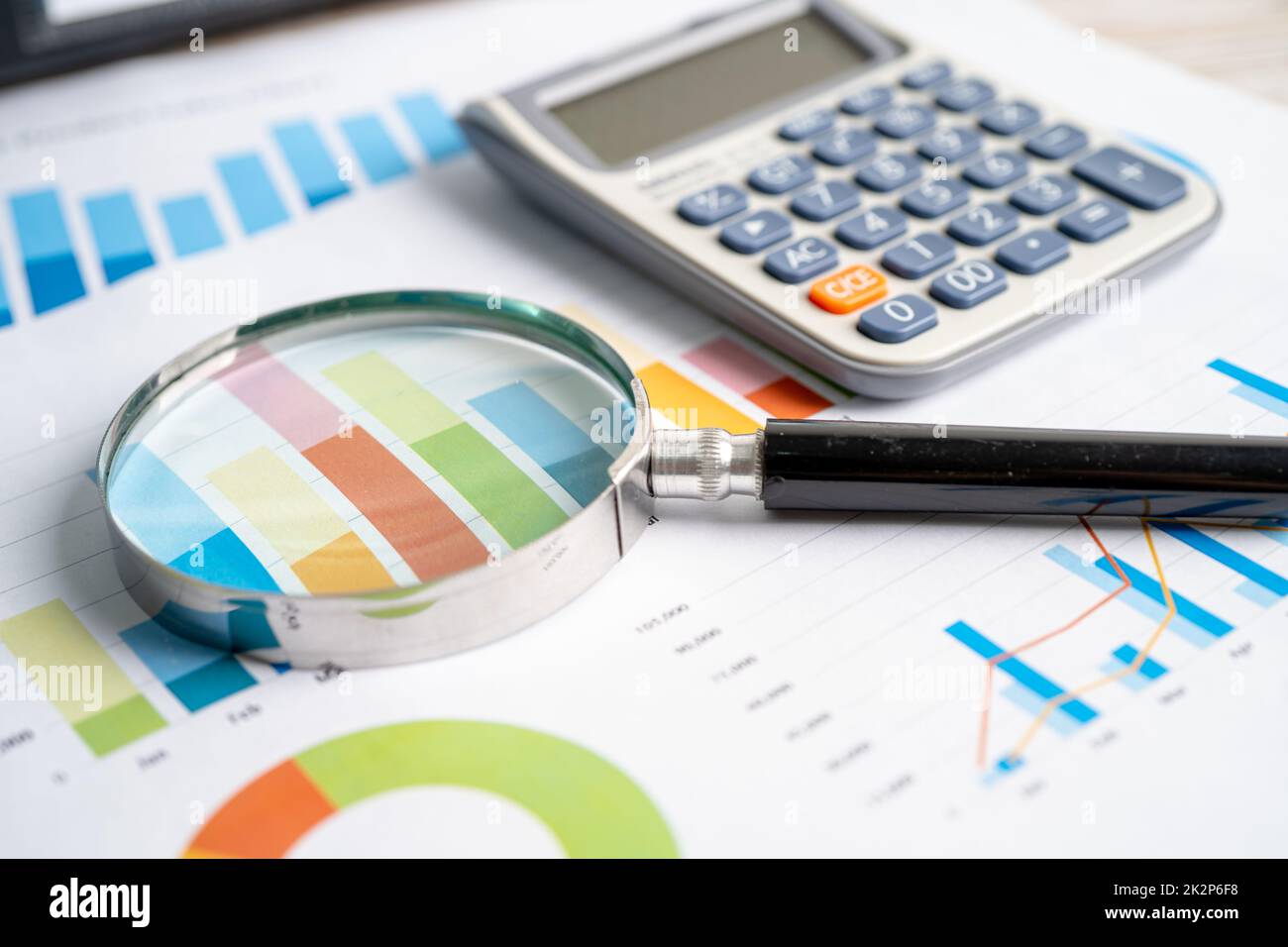Magnifying glass and calculator on charts graphs paper. Financial ...