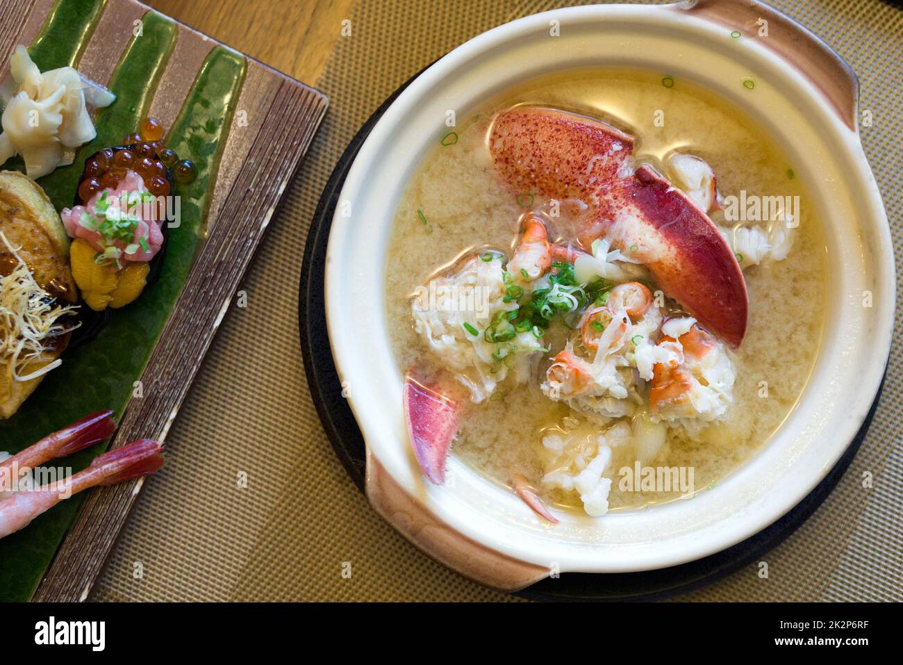 Lobster Nabe in ceramic pot served with sushi set on the table. Top ...