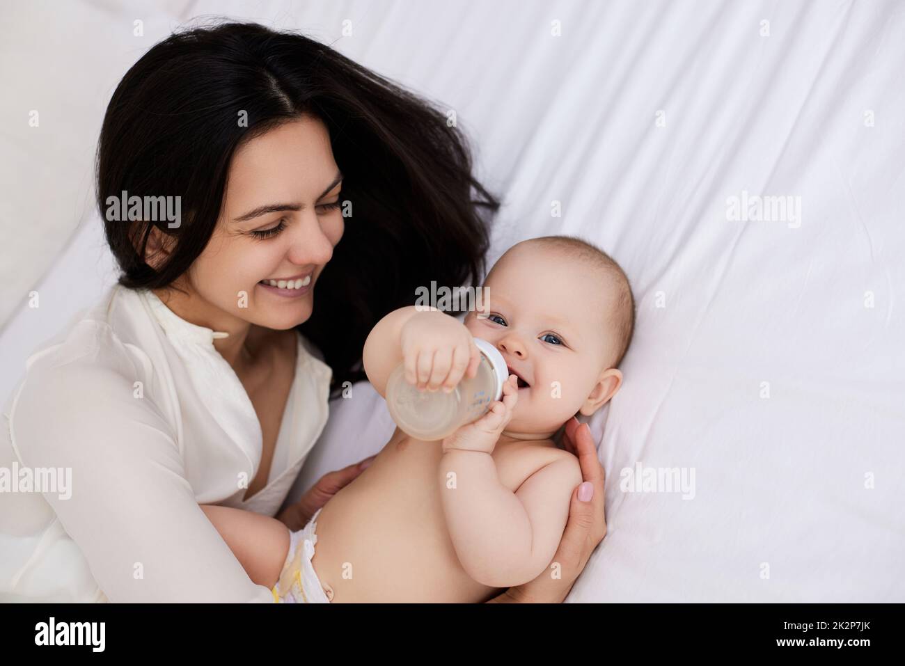 happy mother feeding her newborn baby on the bed Stock Photo - Alamy