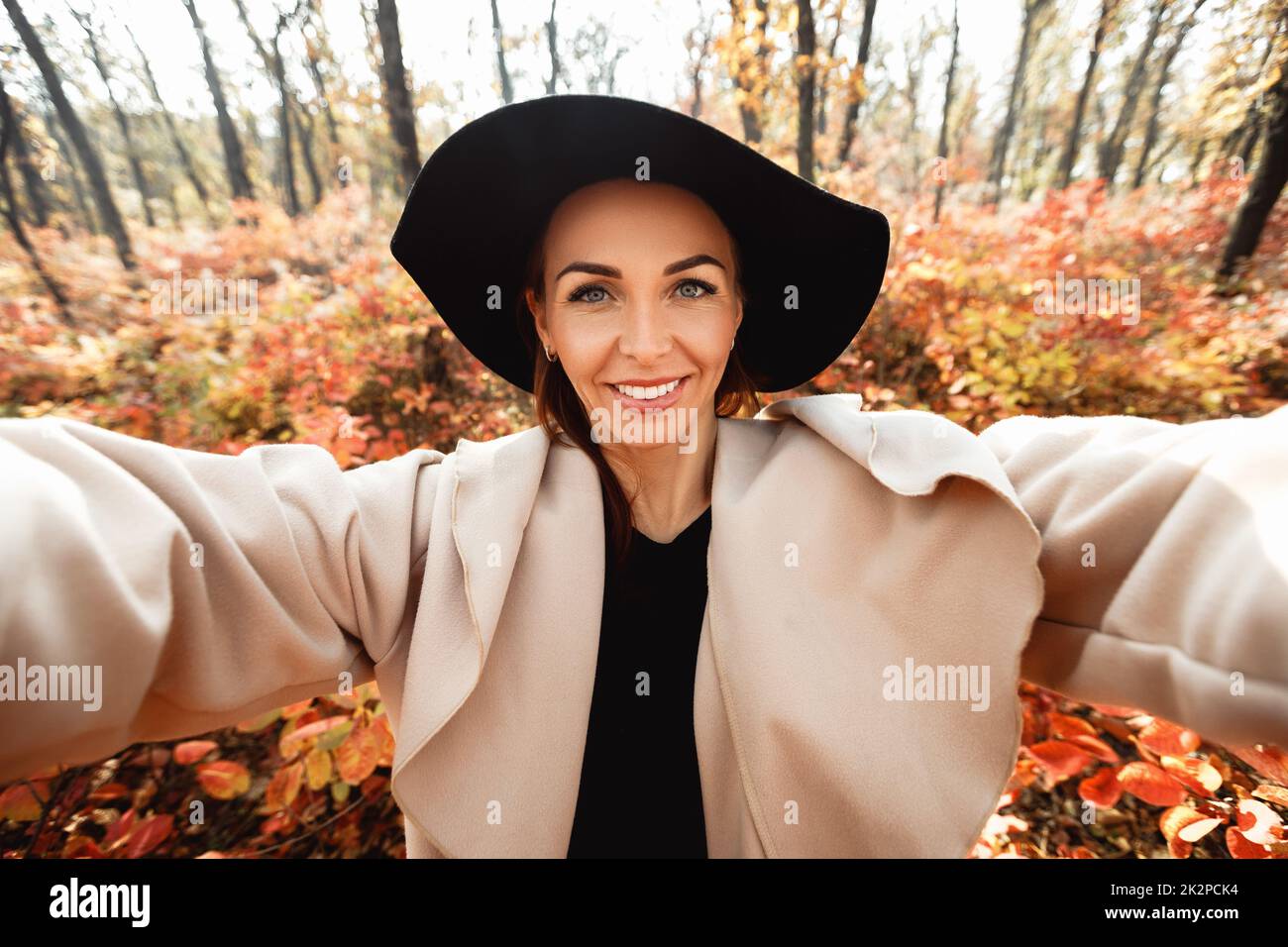 happy woman making selfie in the autumn park full of yellow leaves ...