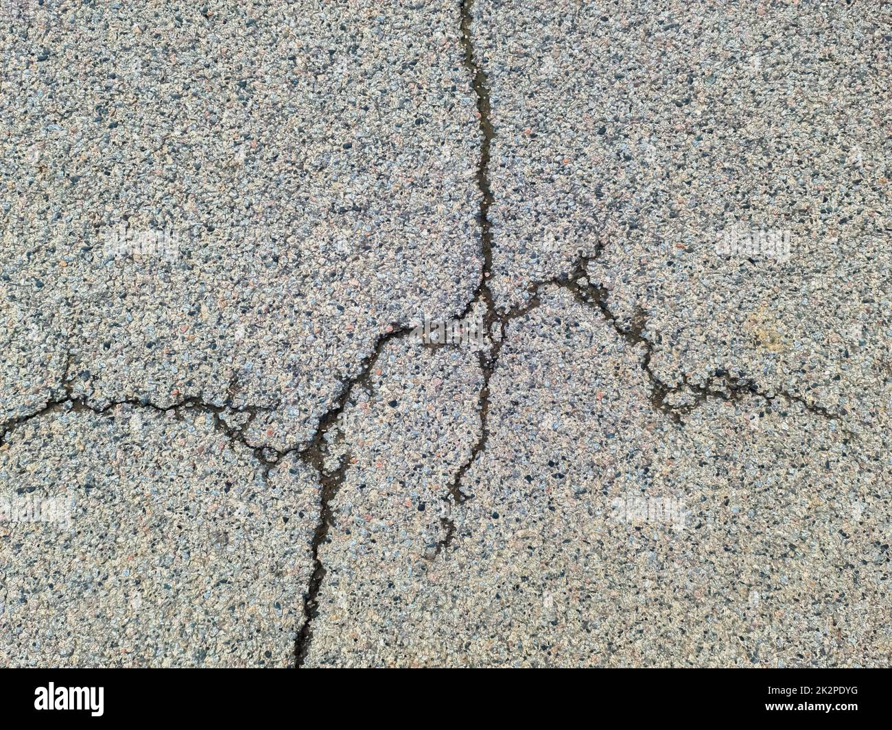 Asphalt surfaces of damaged streets and roads with cracks in a close up ...
