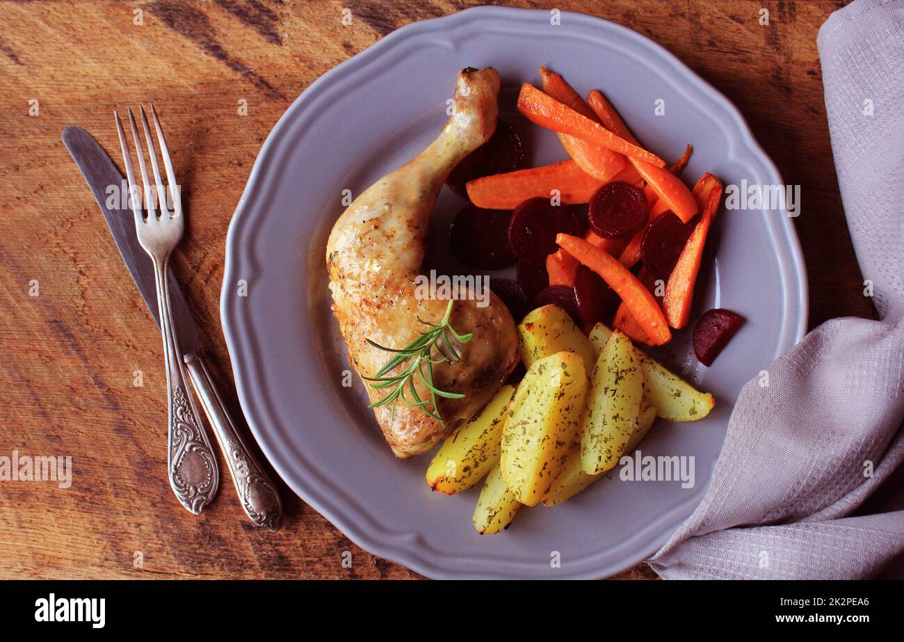 Grilled chicken quarter with beet, carrot for garnish. Top view. Wooden ...