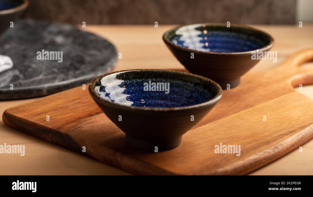 The two brown bowls with blue design placed over the wooden cutting ...