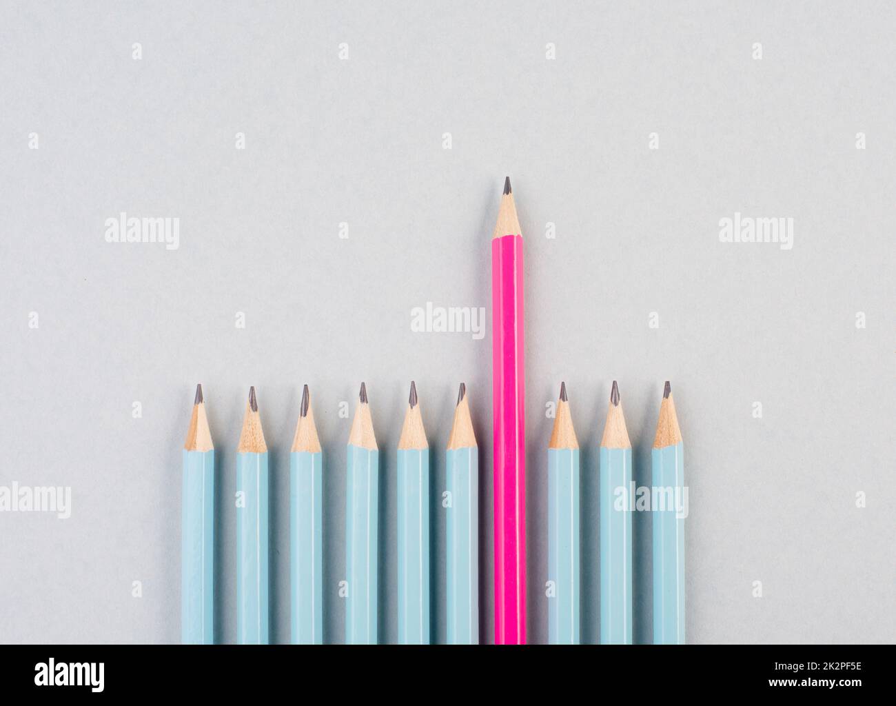 Blue pencils in a row, one pink pen is standing out, be different ...