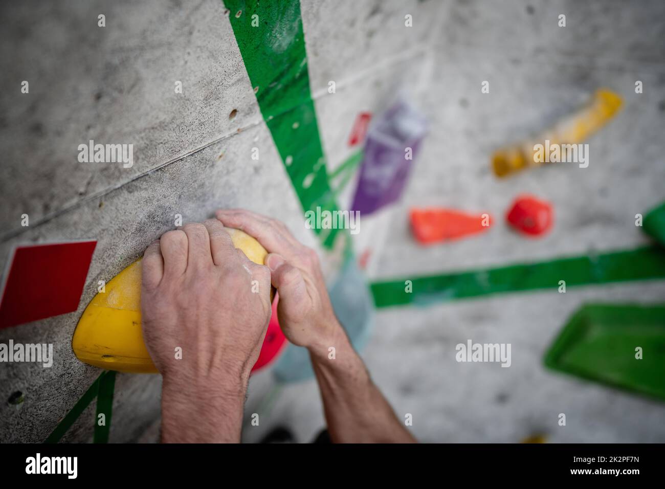 Male hands smeared with magnesium powder grabbing a hold of a climbing ...