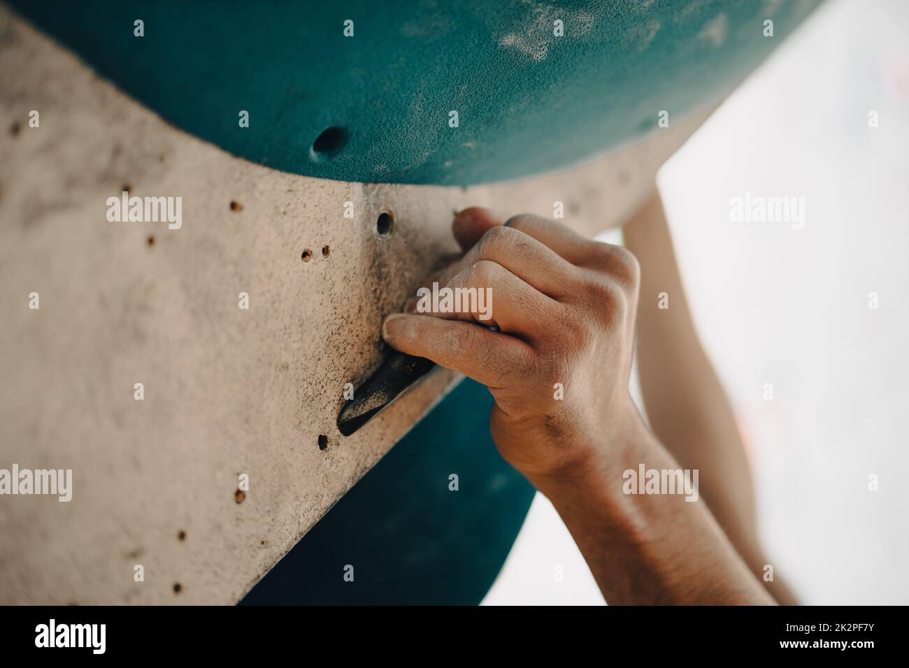 Male hands smeared with magnesium powder grabbing a hold of a climbing ...