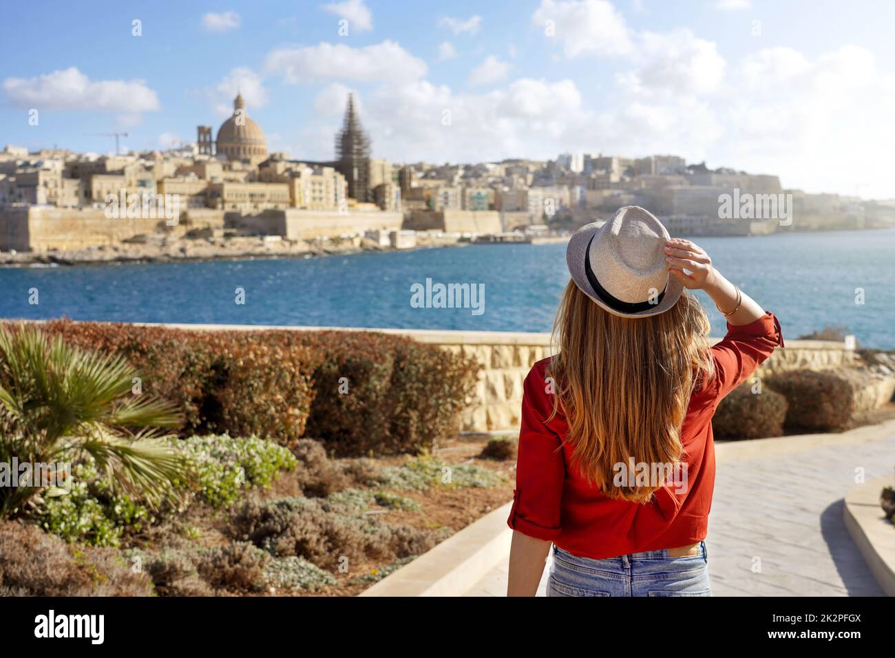 Beautiful young woman with hat goes down along Malta waterfront looking ...
