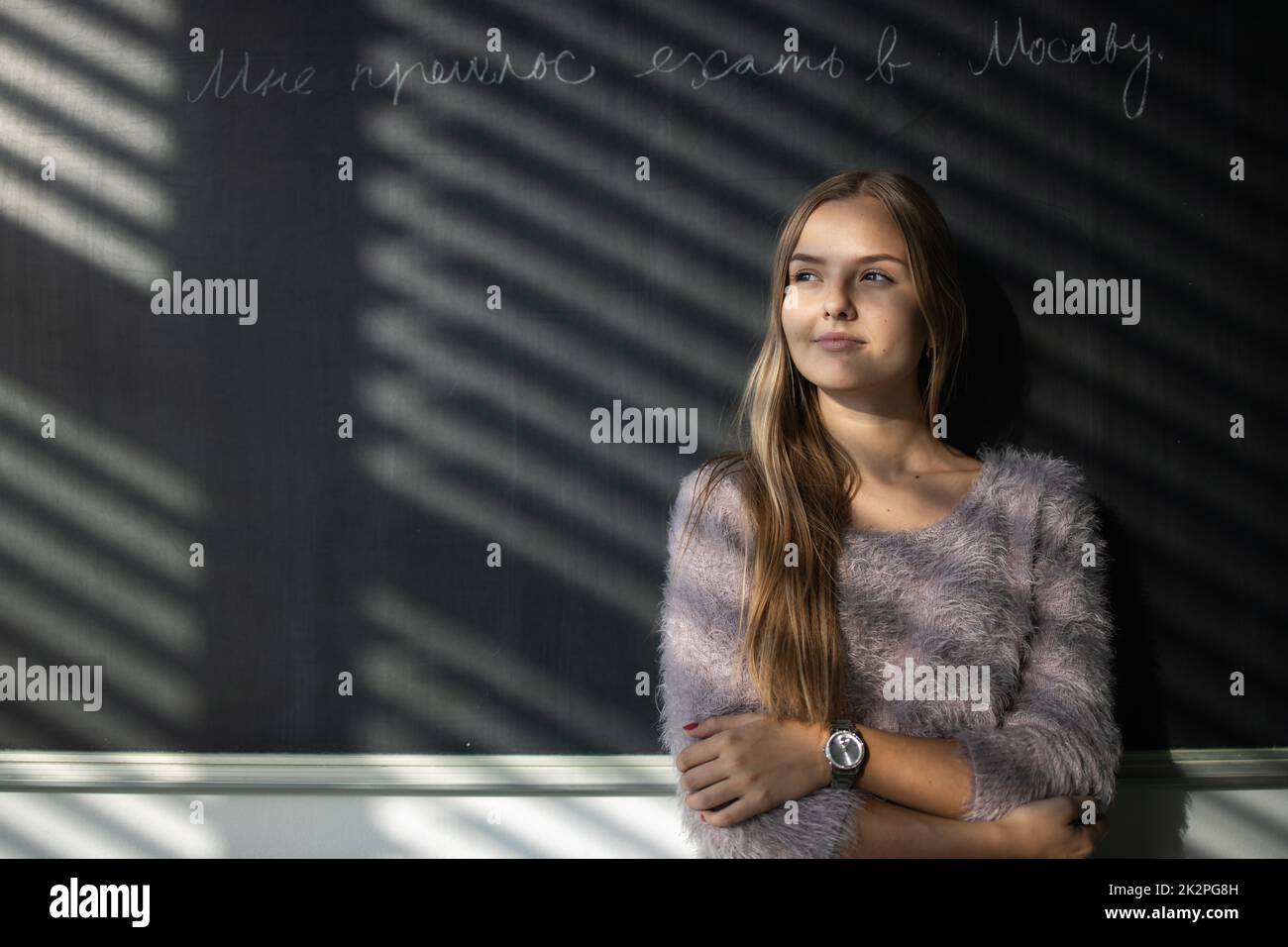 Pretty, young female student in front of a blackboard during class ...
